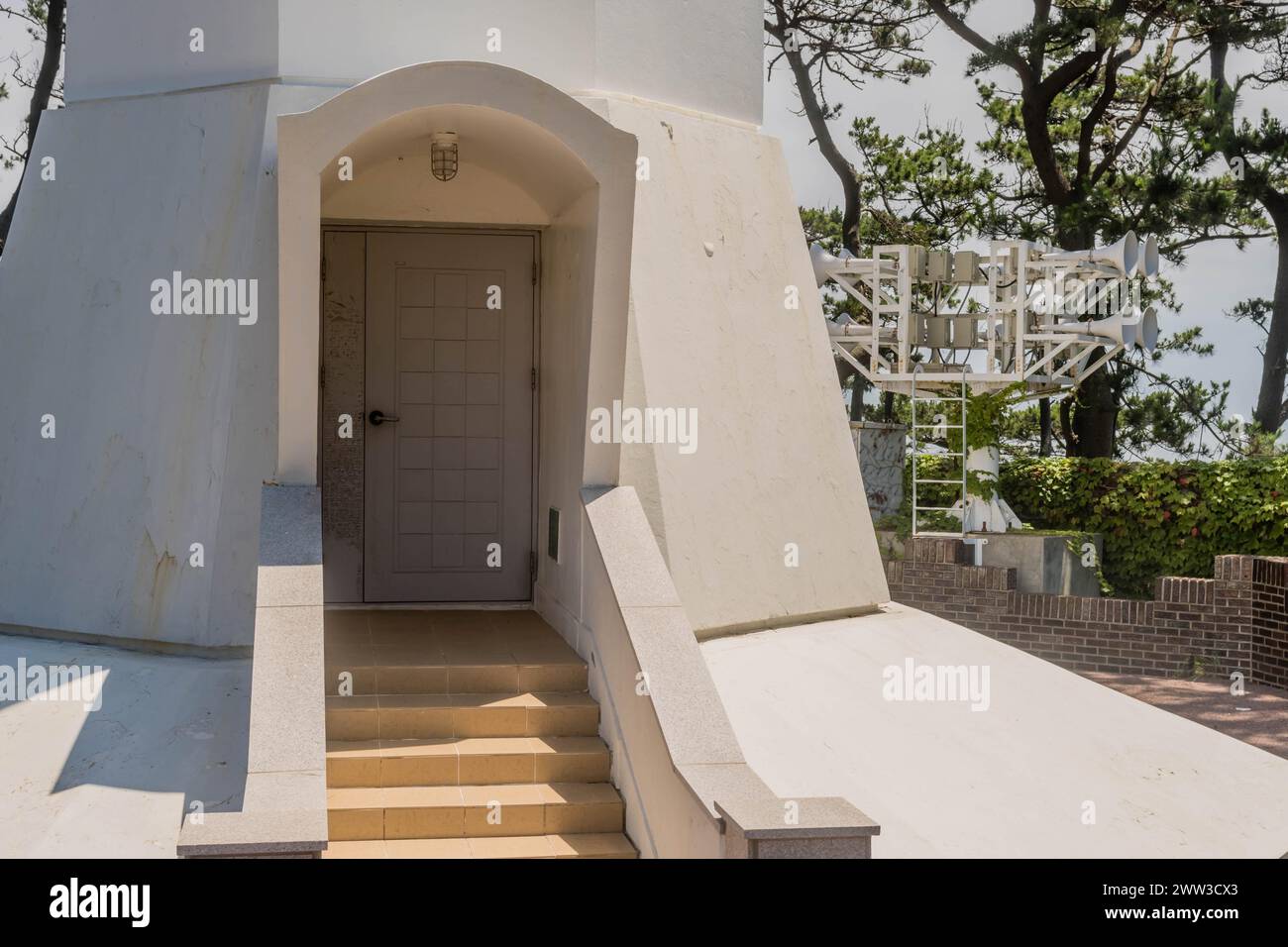 The entrance of a white lighthouse tower with a small staircase leading ...