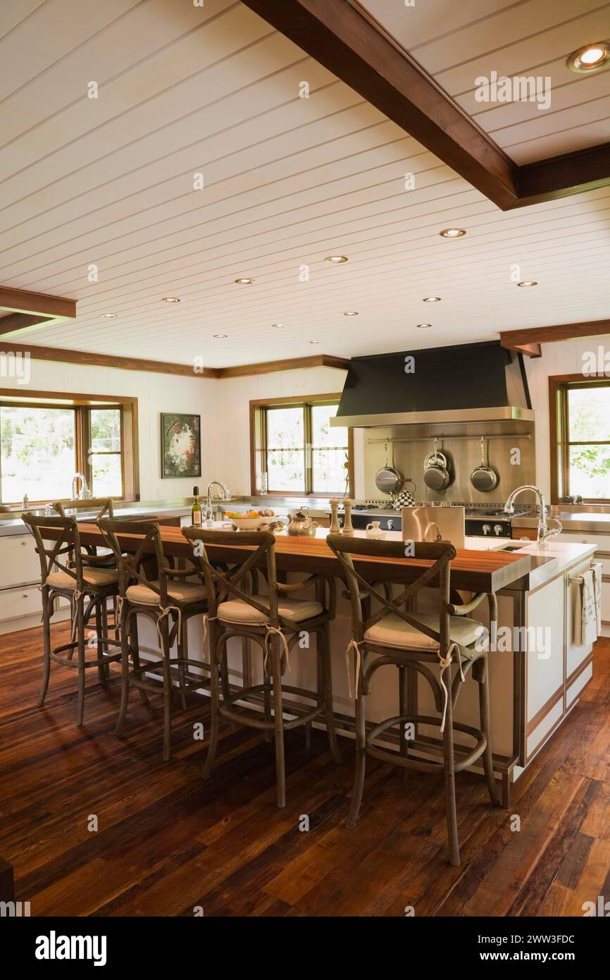 Country style kitchen with island and rustic wooden high chairs inside ...