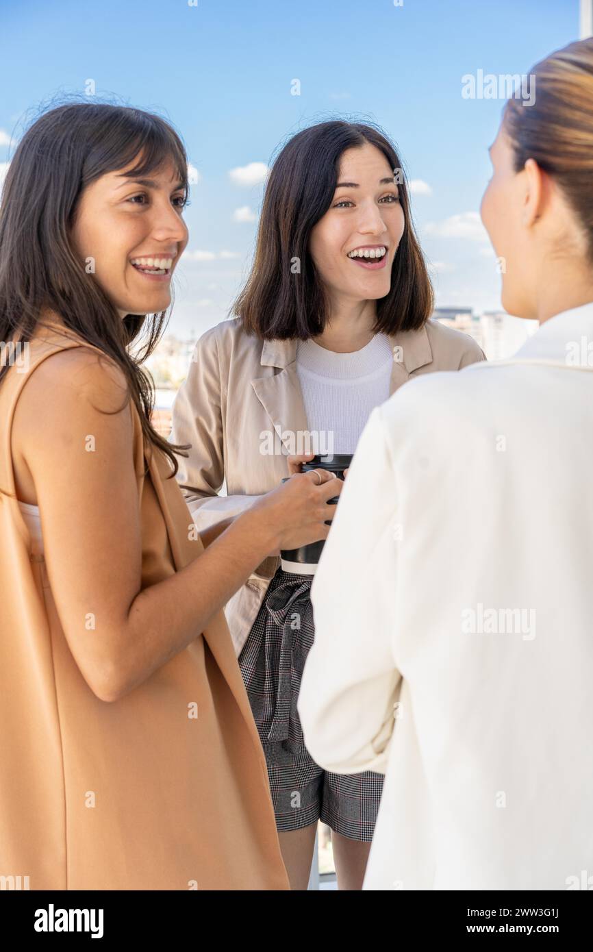 Three female business colleagues are savoring their coffee and sharing ...