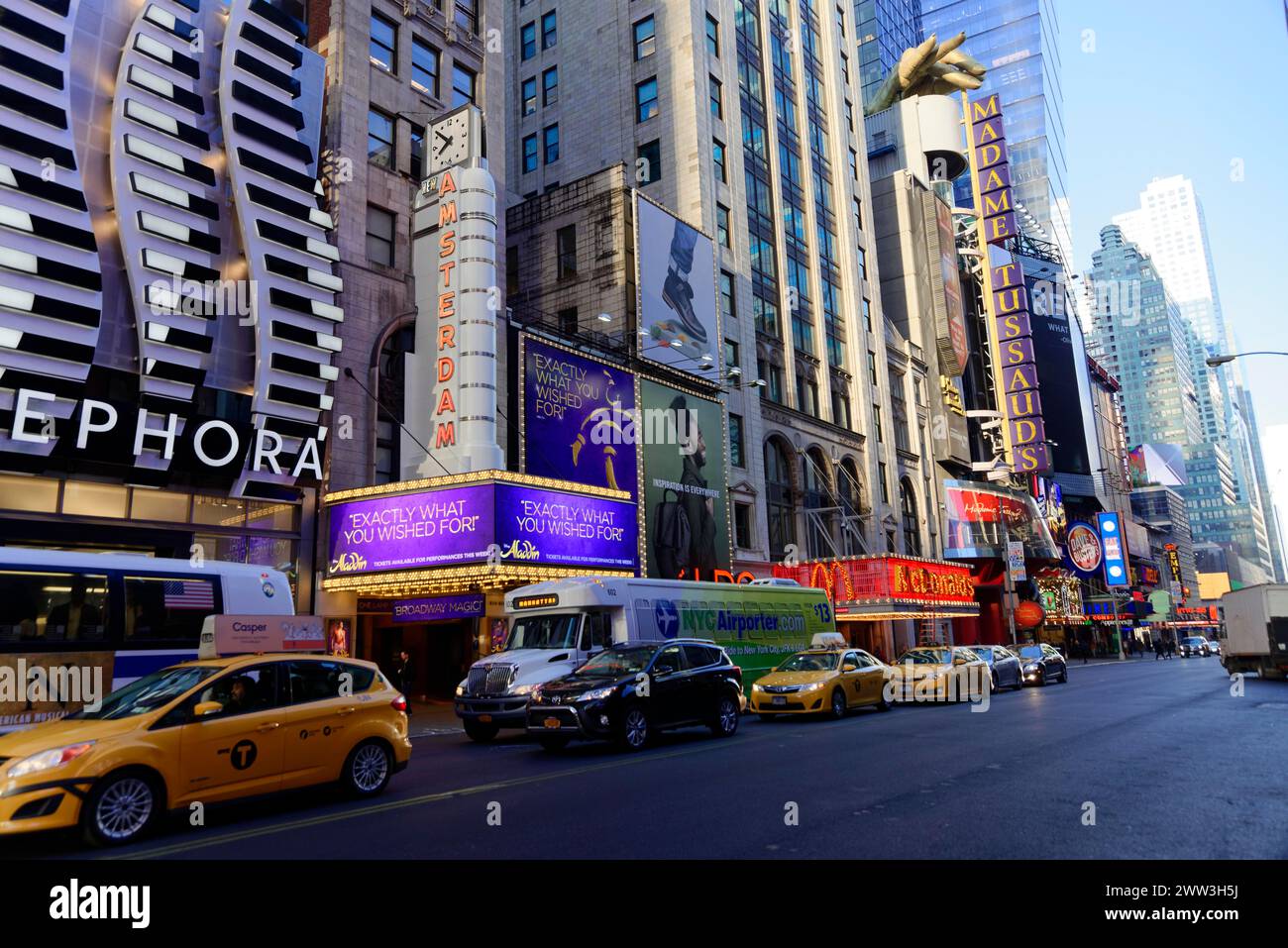 Busy urban street with taxis, passers-by and a row of shops and ...