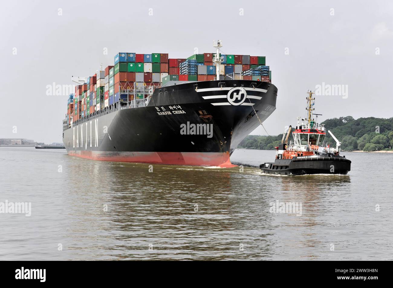 HANJIN CHINA, Large black container ship being guided by a tugboat ...