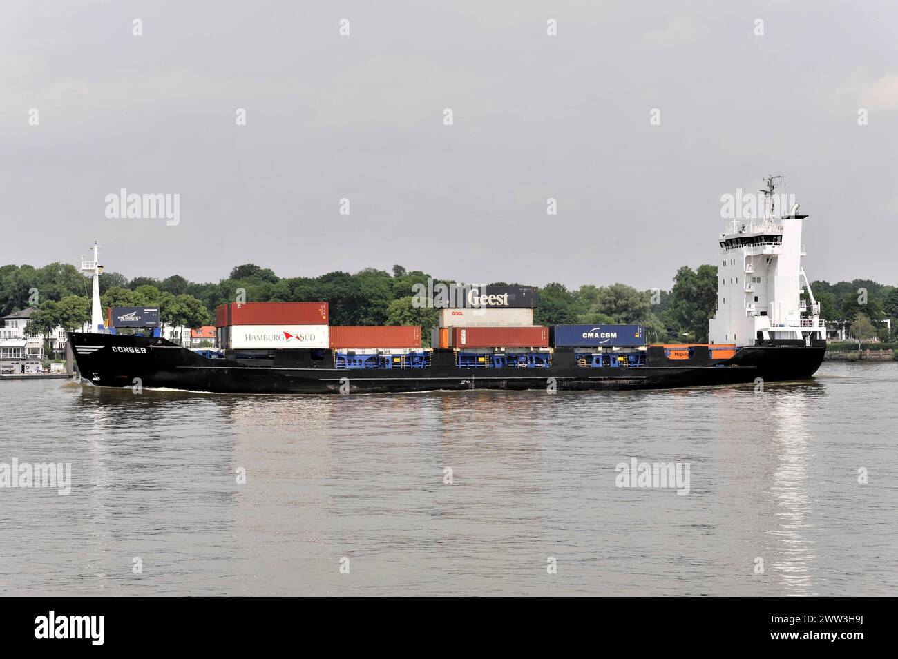Gonger, A small container ship on the water with a city background ...