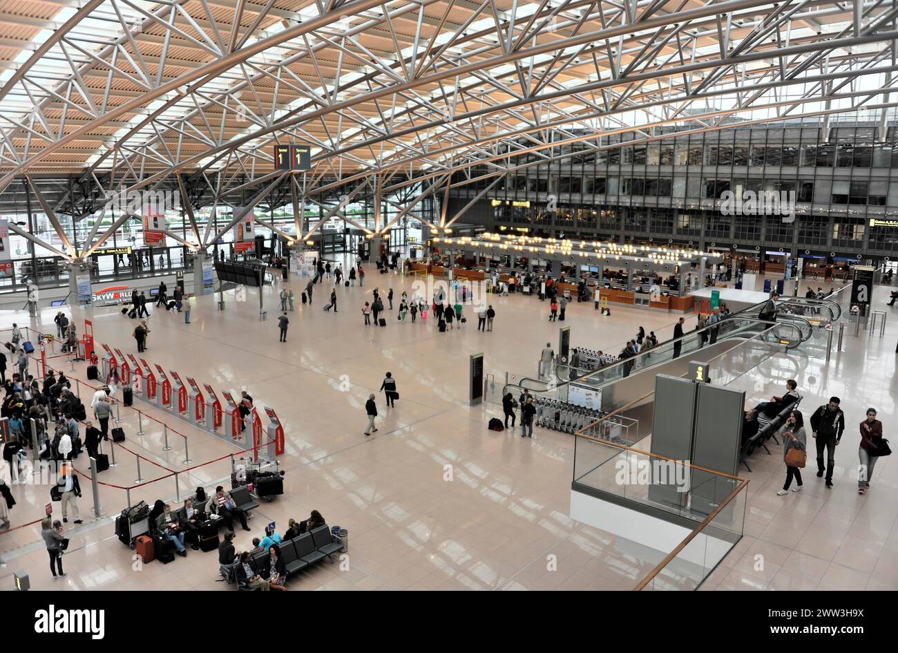 Spacious view of an airport terminal with travellers and a modern roof ...