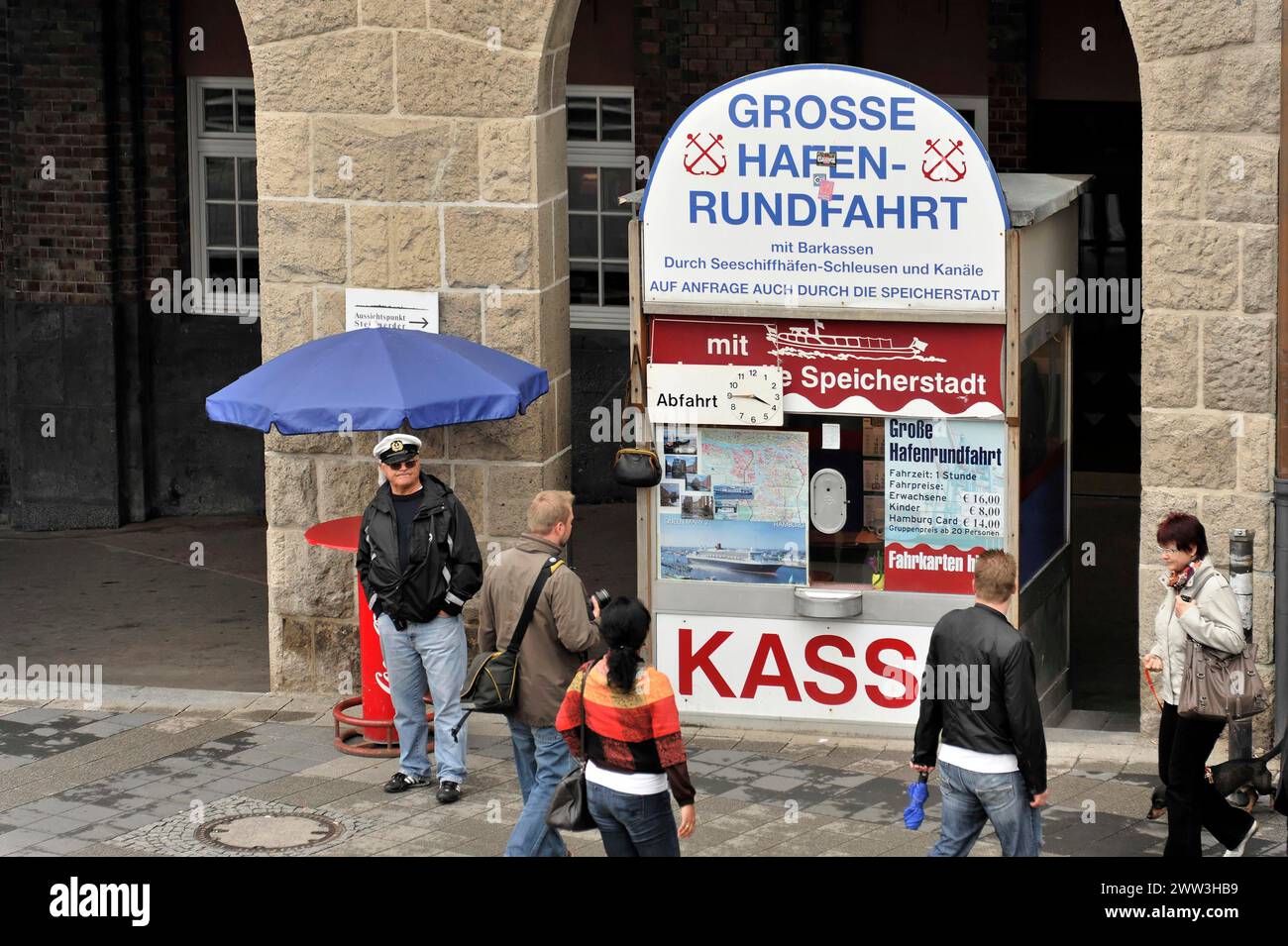 People standing in front of a kiosk for harbour tours in an urban ...