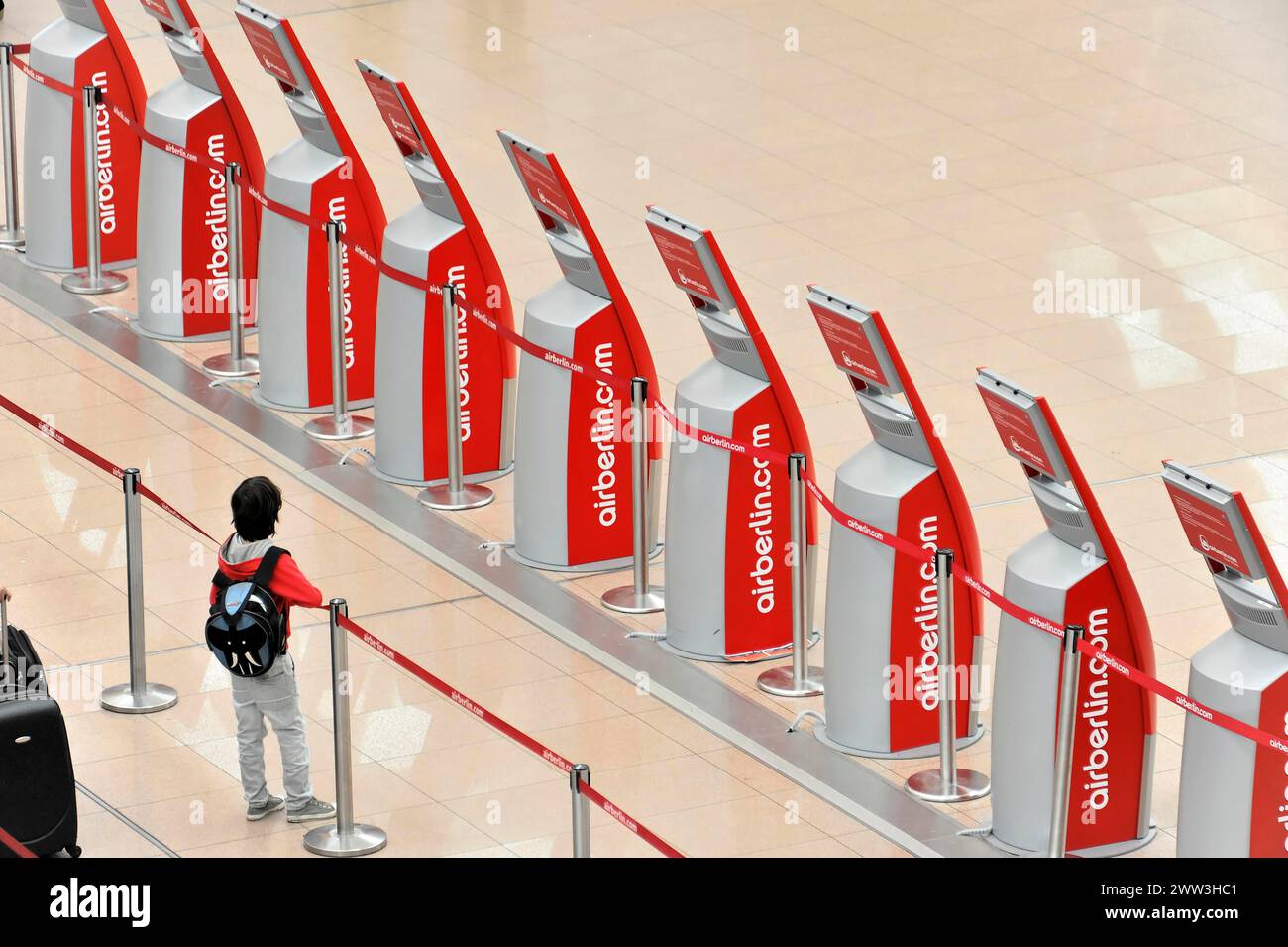 A child standing in front of self-service check-in machines in an ...