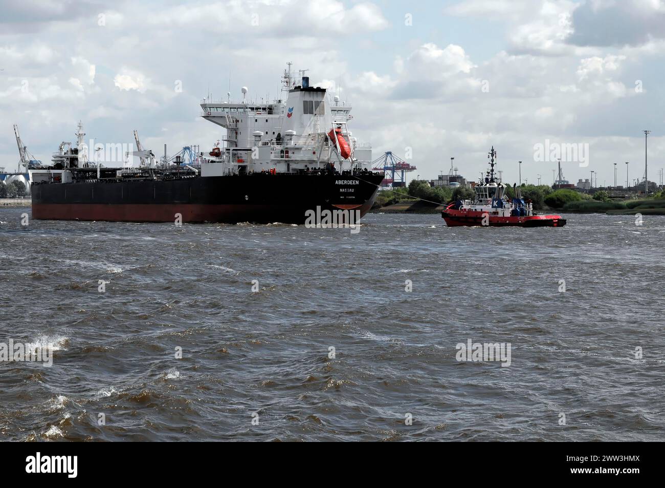 A tanker and a tugboat in the turbulent waters of a harbour, Hamburg ...