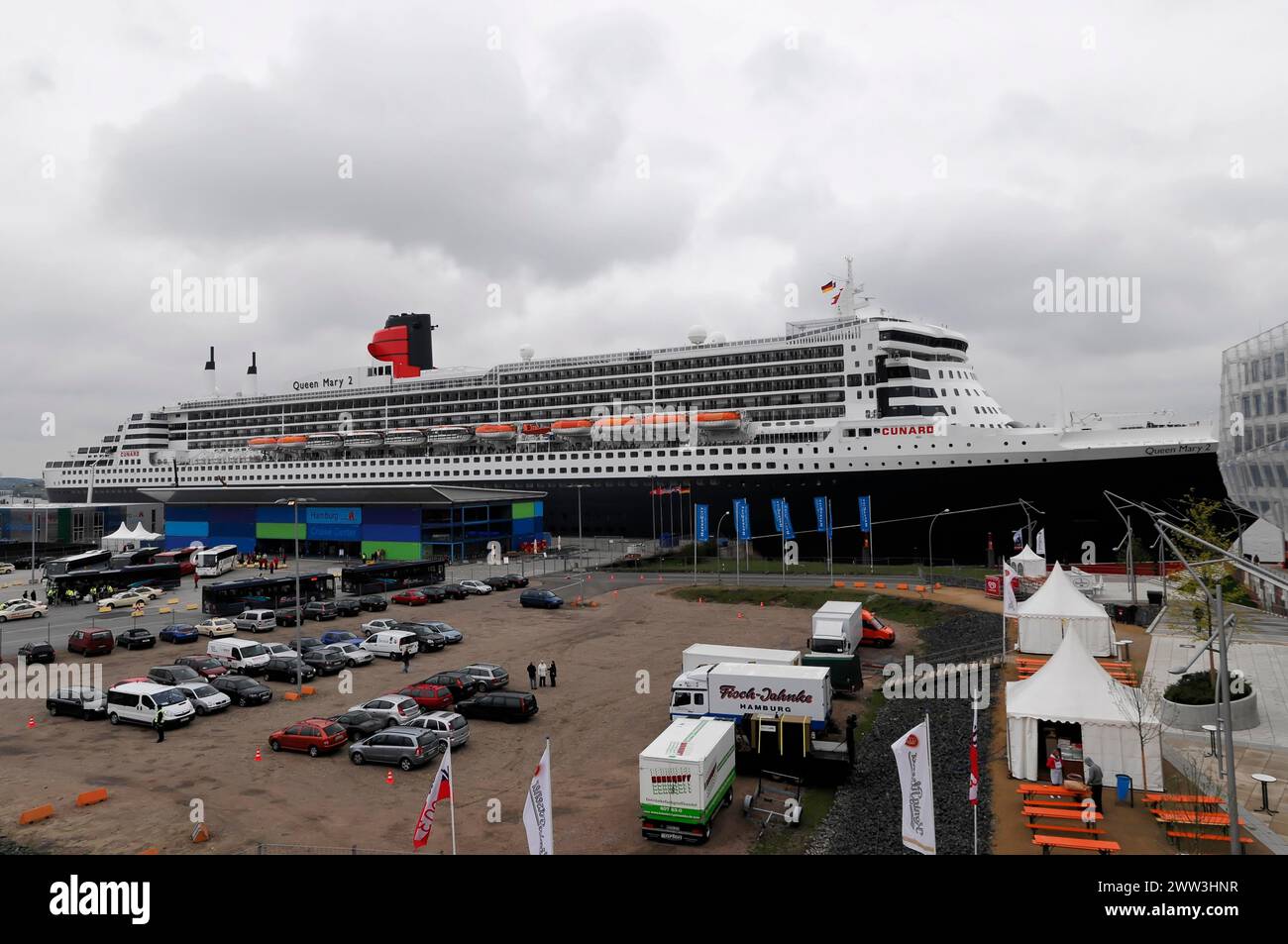 Large cruise ship Queen Mary 2, at a harbour with parked vehicles and ...