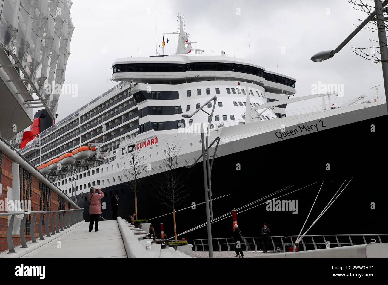 A large cruise ship Queen Mary 2, at the dock, people walking on the ...