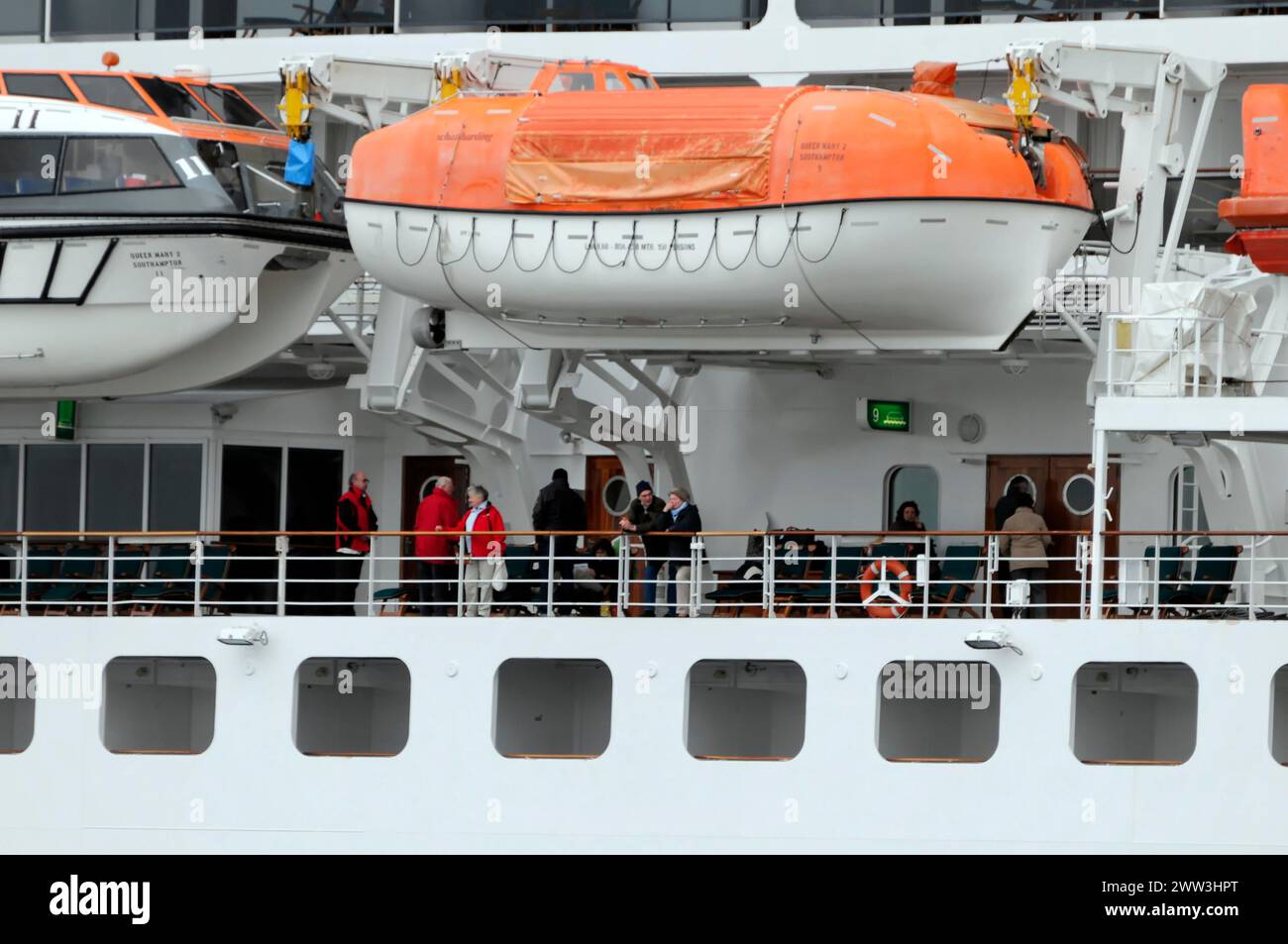 Passengers stand next to lifeboats on board the Queen Mary 2, Hamburg ...