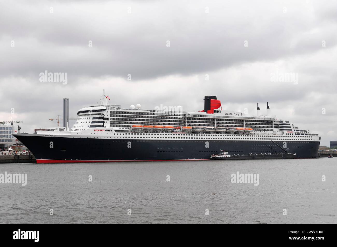 Side view of a large Cunard cruise ship Queen Mary 2, on a cloudy day ...