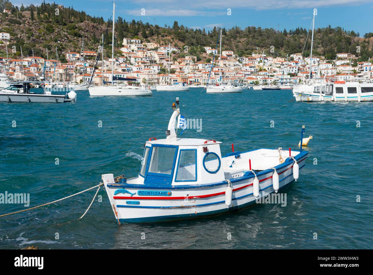A moored boat in a quiet harbour with a view of sailing boats and white ...