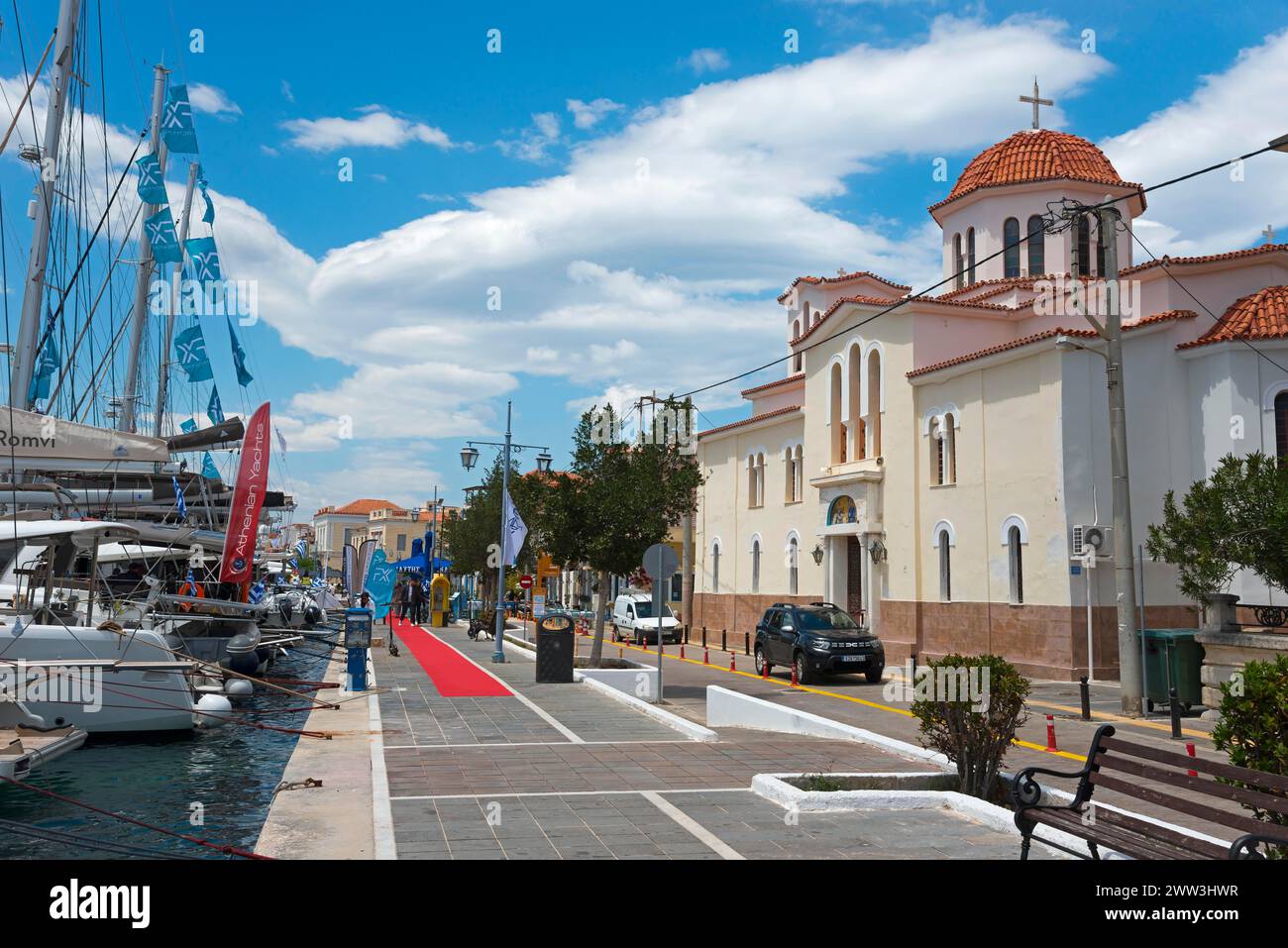 A picturesque harbour view with a church, yachts and a promenade under ...