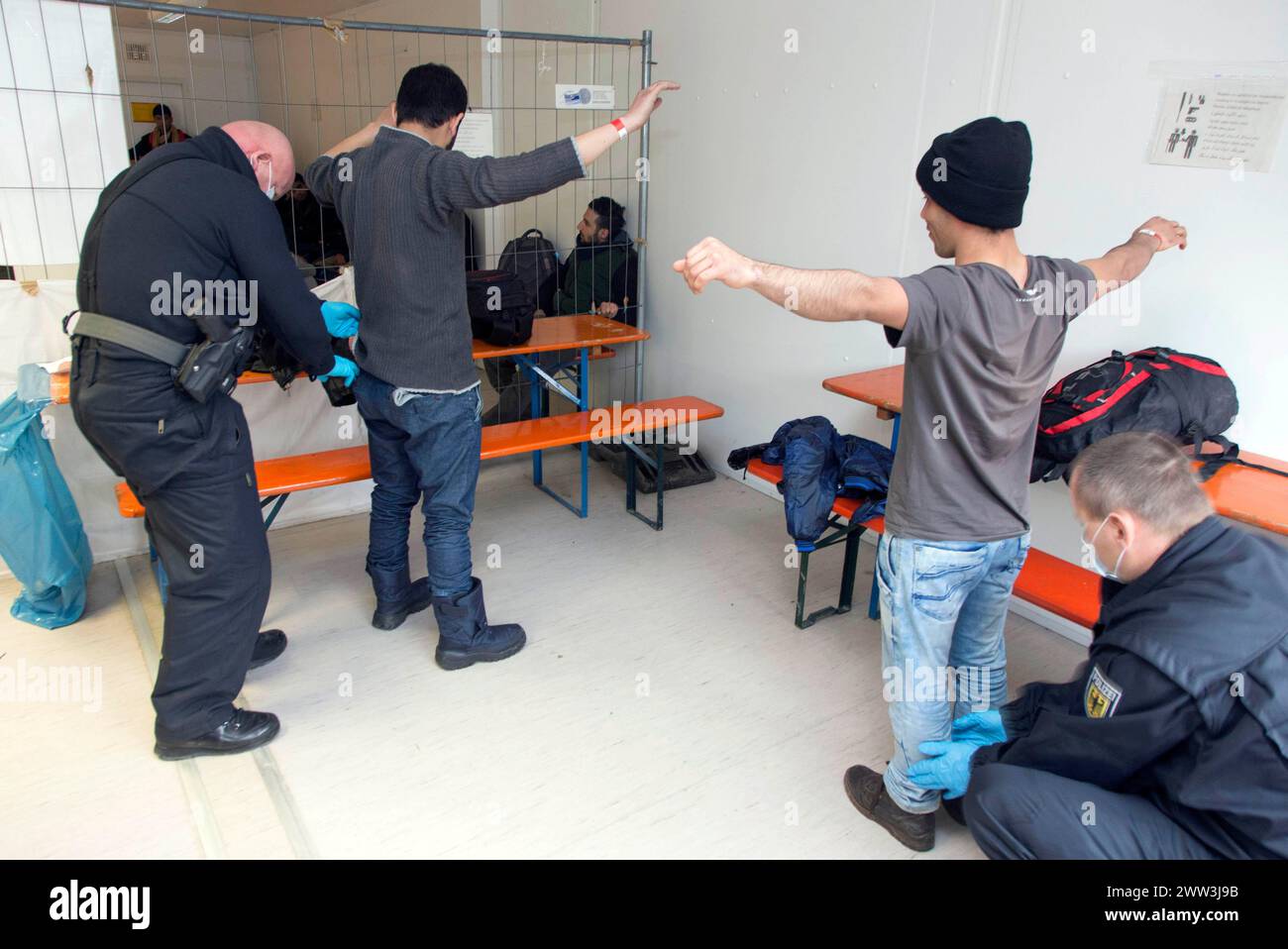 Refugees are searched by federal police officers after their arrival at ...