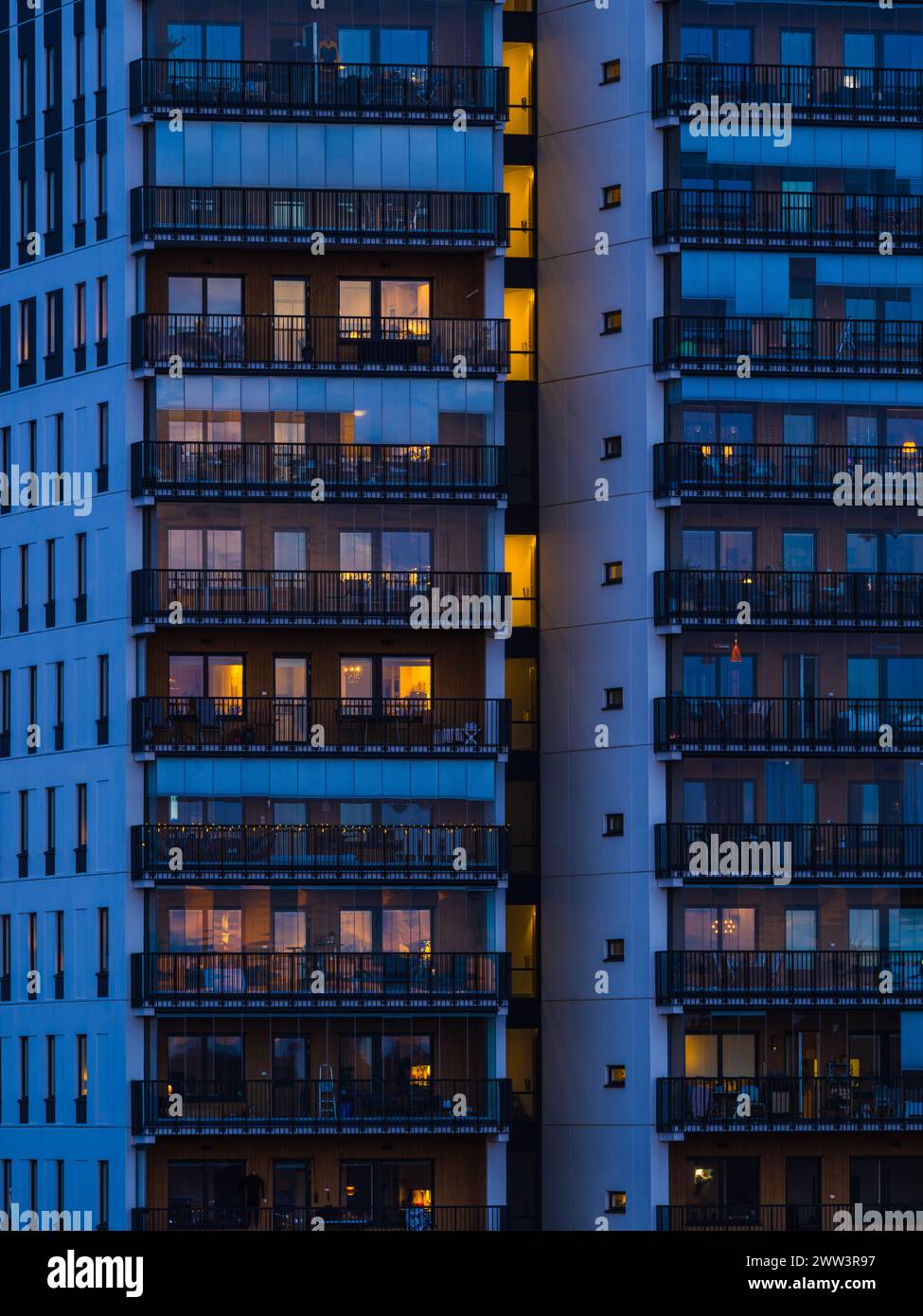 A tall building with numerous balconies is illuminated at night ...