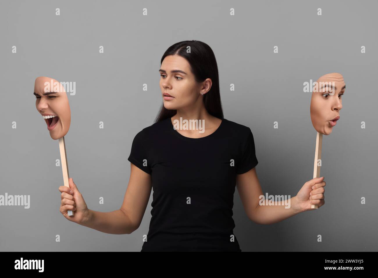 Woman holding masks with her face showing different emotions on grey ...