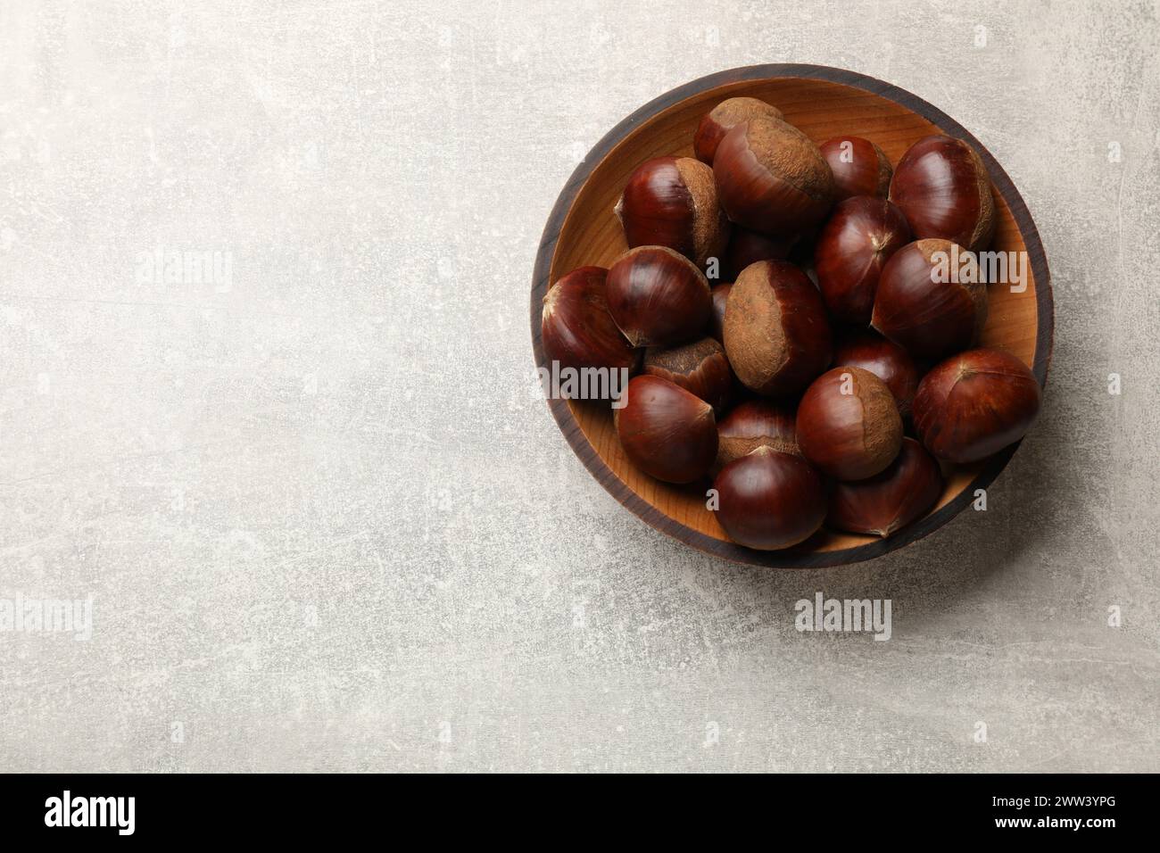 Roasted edible sweet chestnuts in bowl on light grey table, top view ...