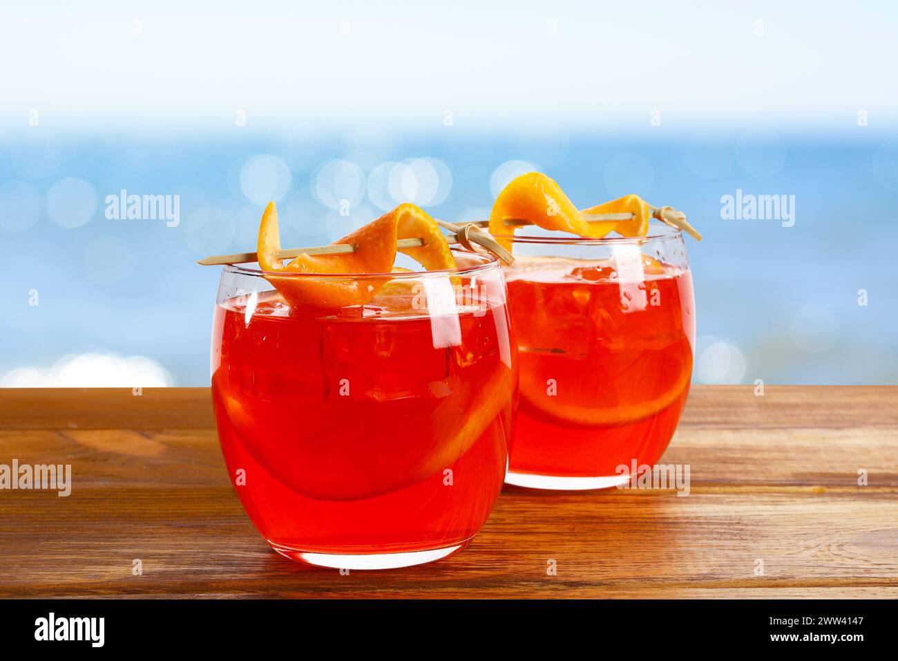 Aperol spritz cocktail with orange slices on wooden table at beach ...
