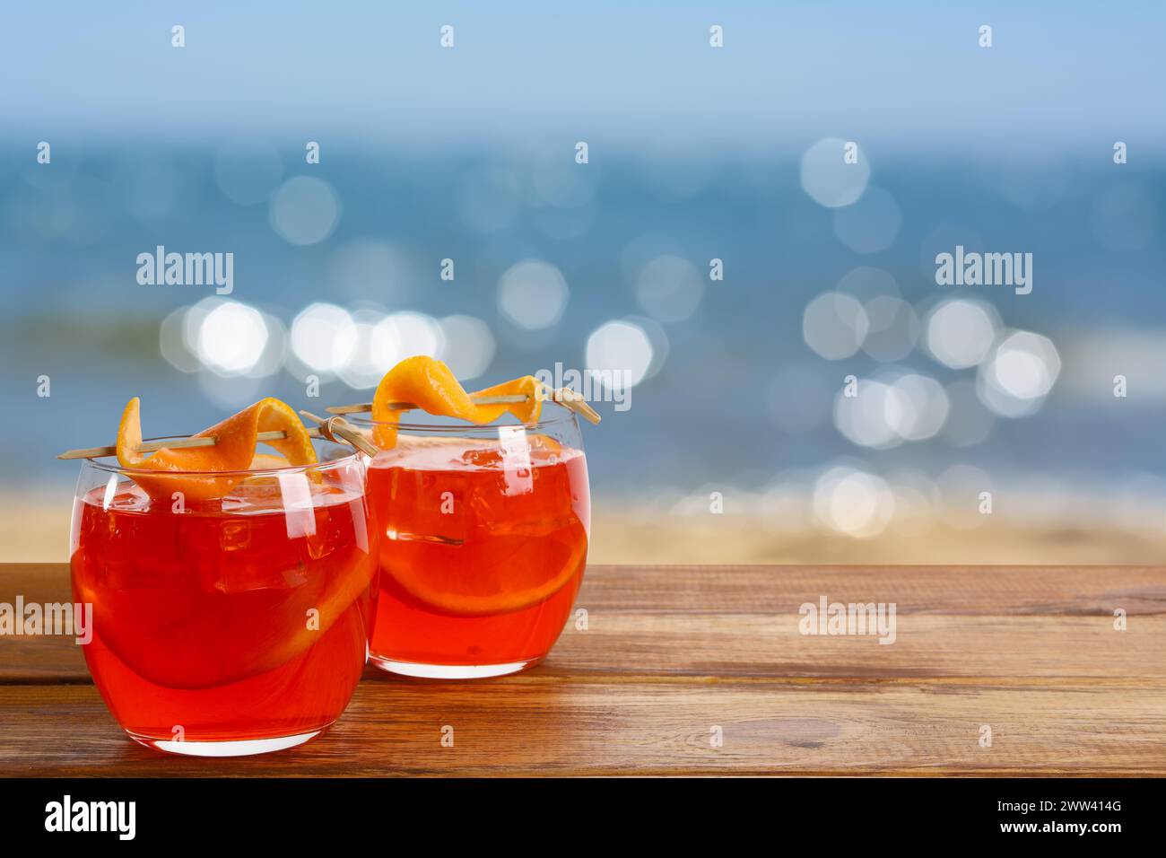 Aperol spritz cocktail with orange slices on wooden table at beach ...