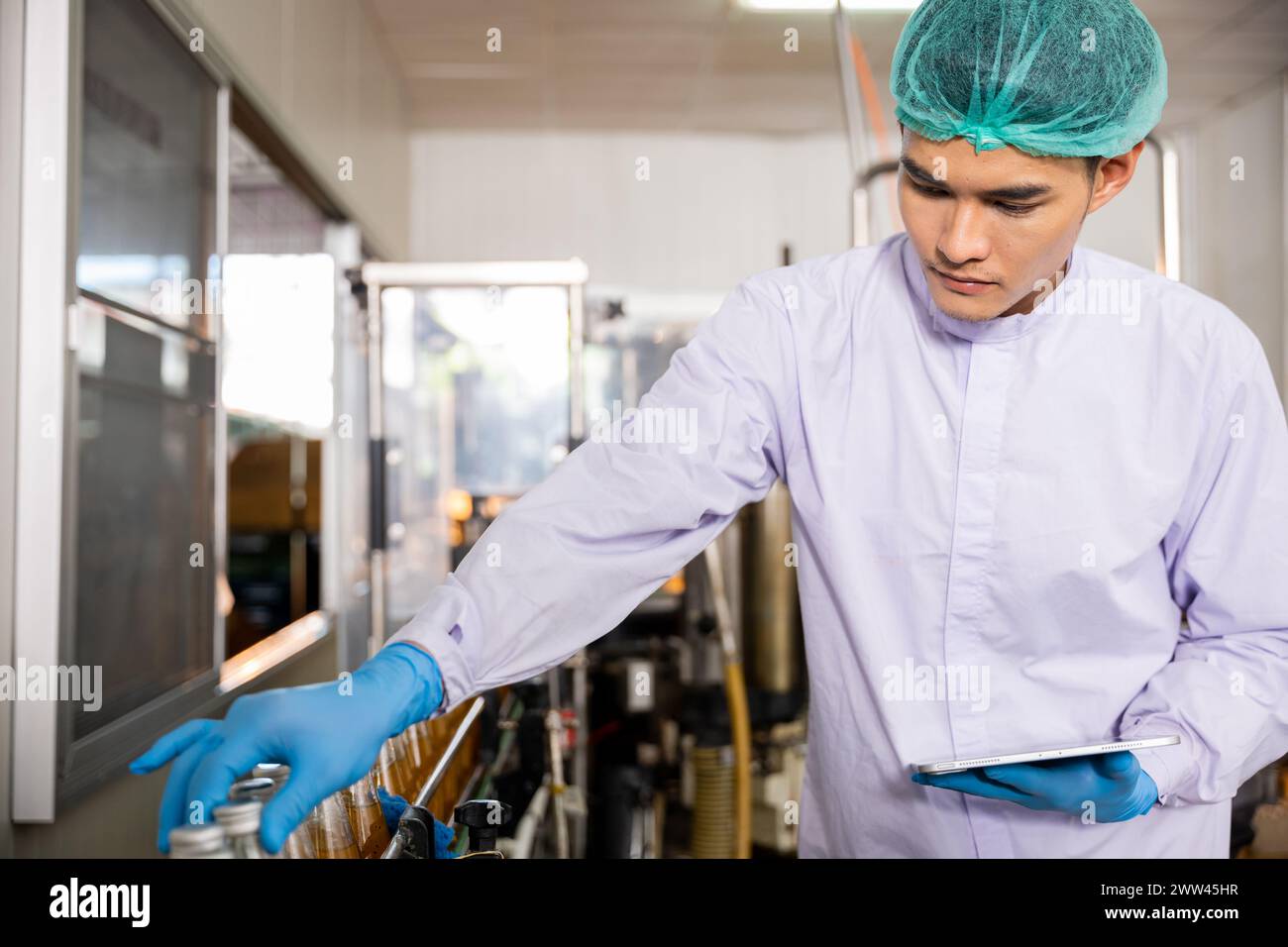 Quality control officer inspects beverage bottling factory line with ...