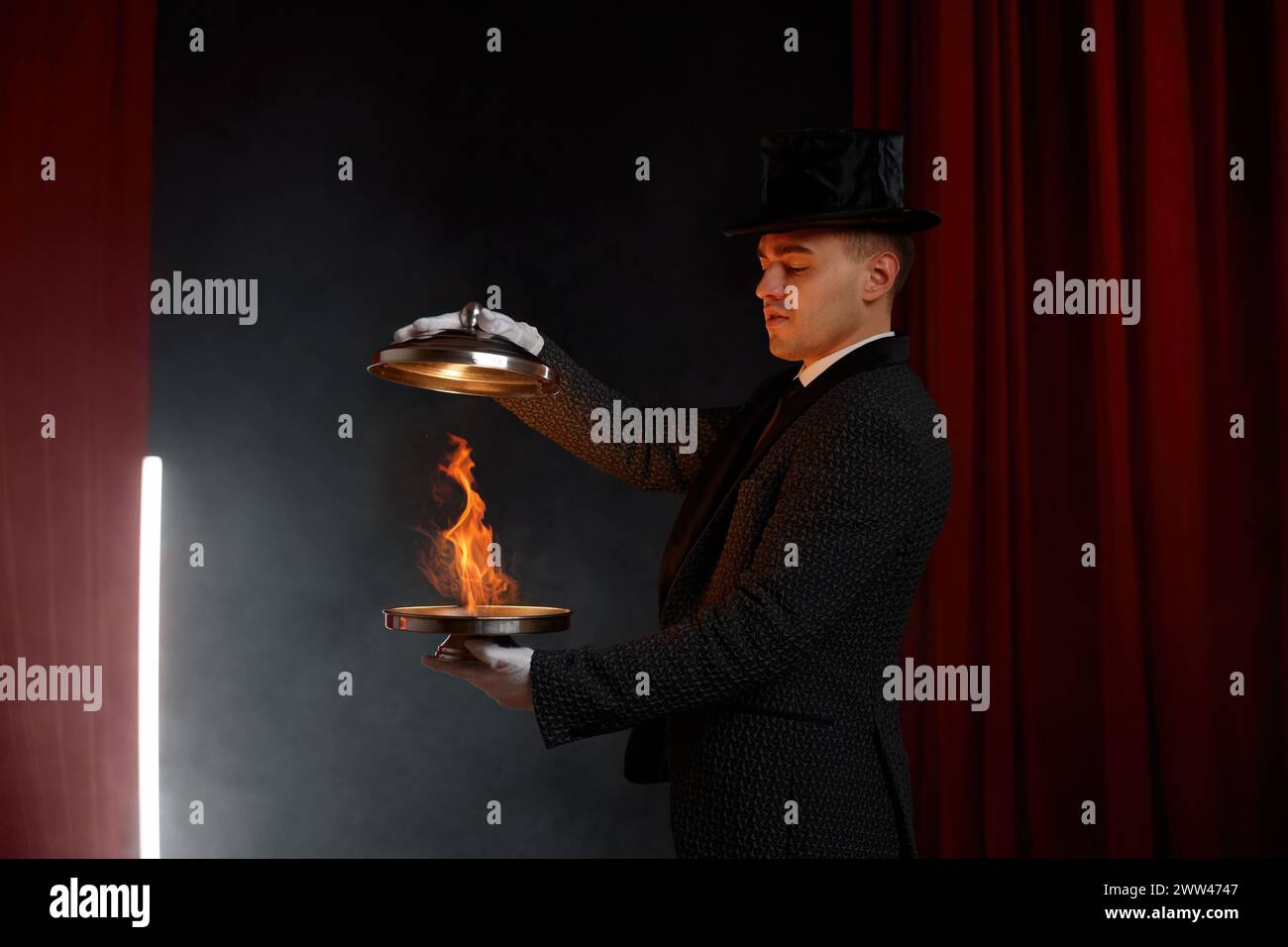 Male magician showing trick with magic fire illusion with steel tray ...