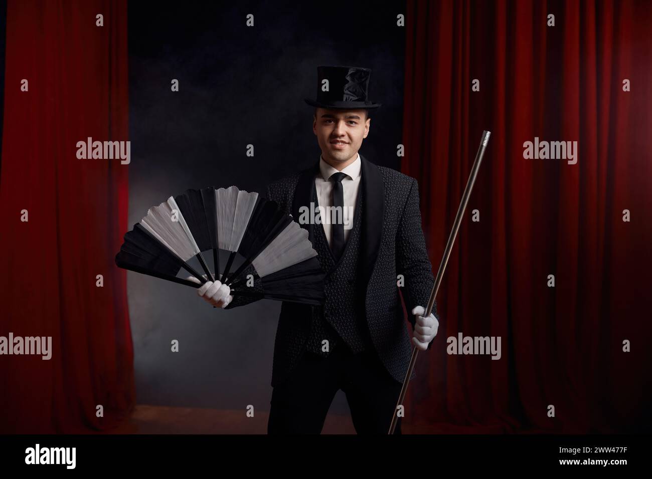 Magician performing miracle trick on stage using fan and cane Stock ...
