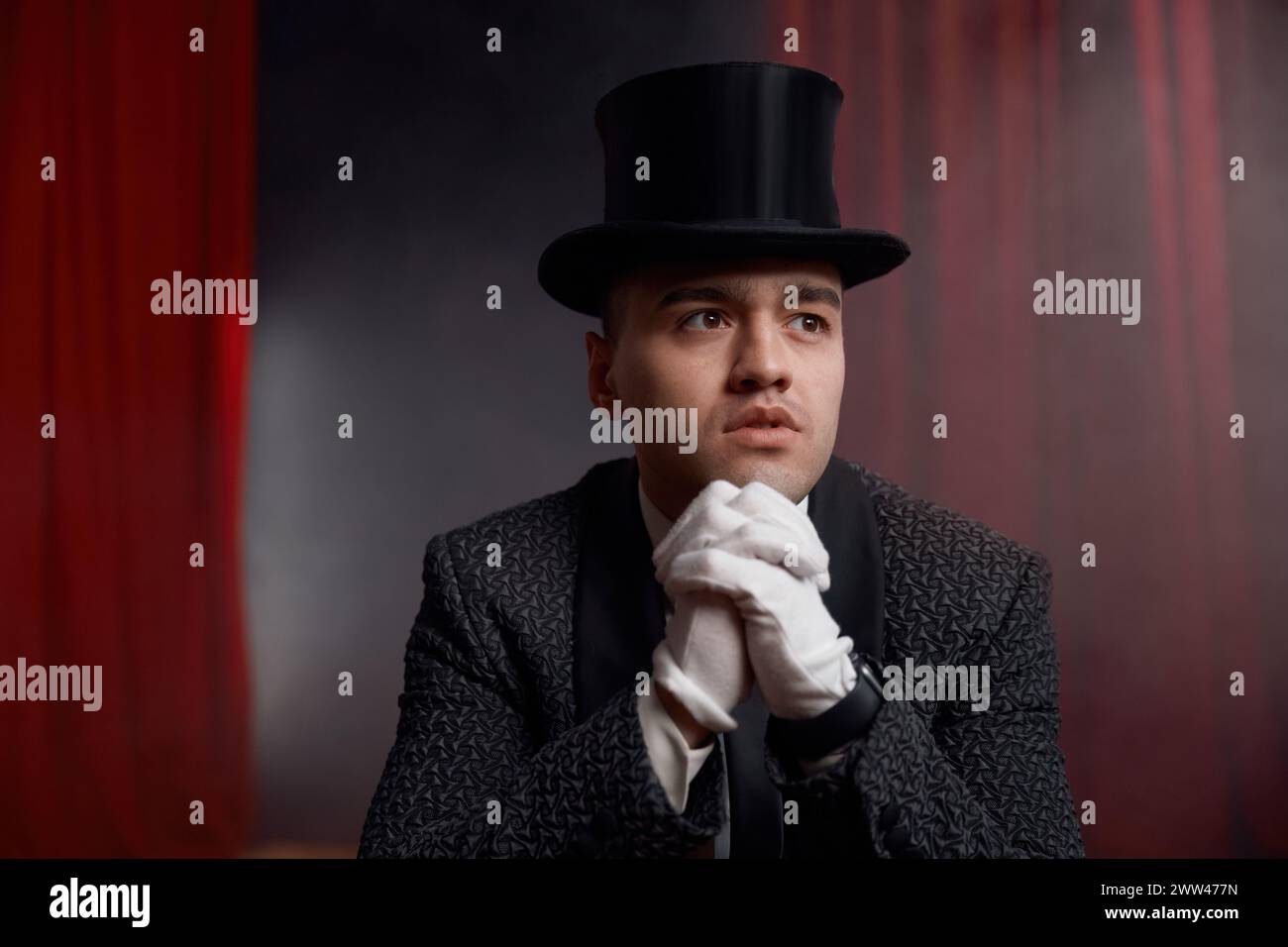 Magician wearing top hat and tuxedo suit holding magic cards in hands ...