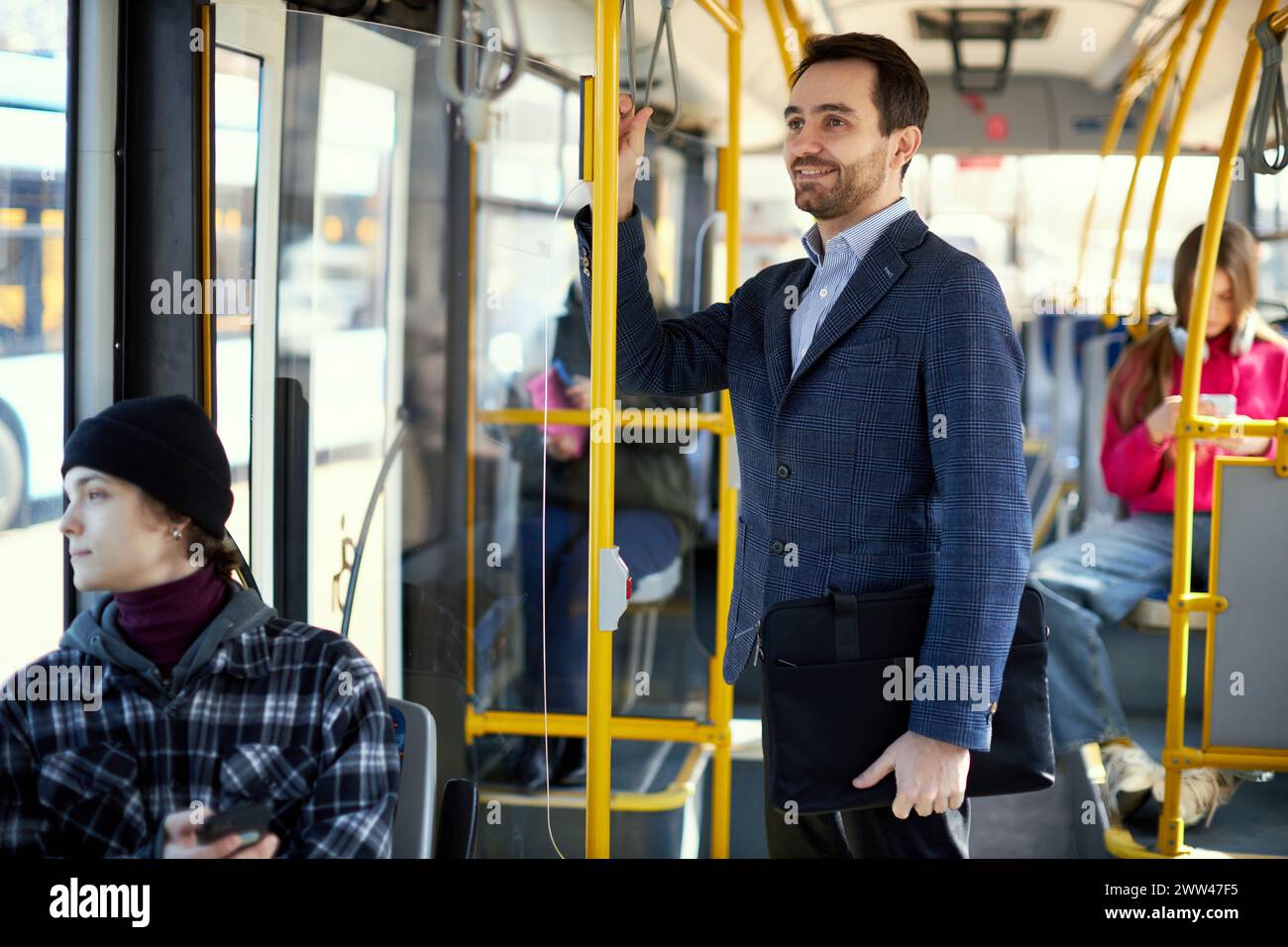 Focus on smiling man in jacket using public transport, modern tram for ...
