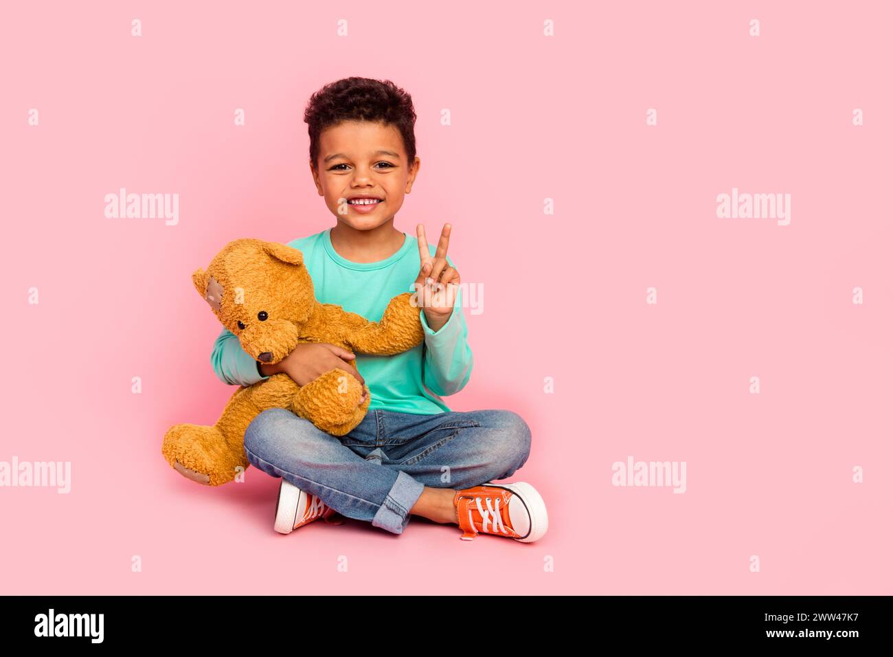 Full body photo of cute little boy sit floor show v-sign hold teddy ...