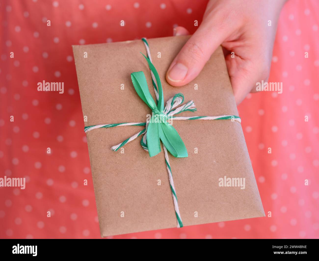 A woman giving a small present with a green bow Stock Photo - Alamy