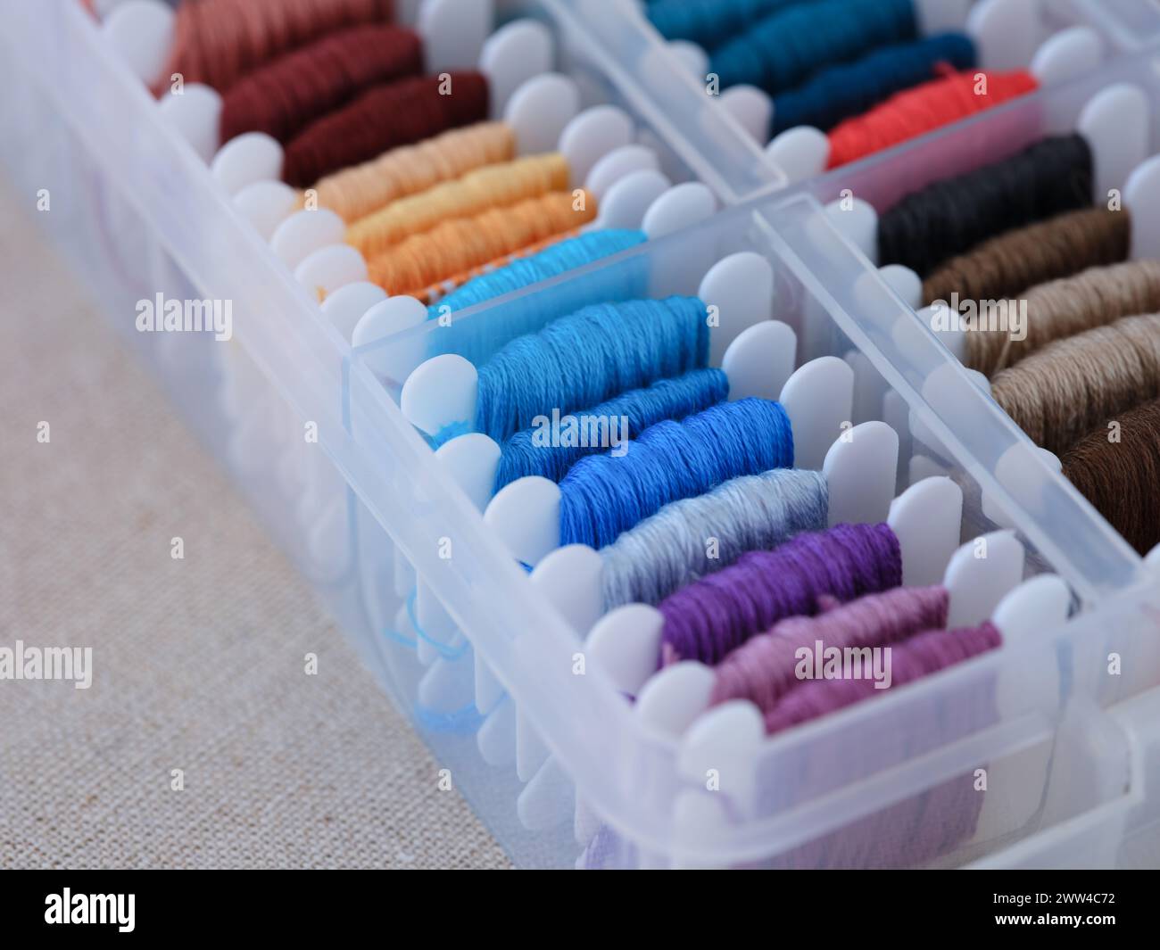 A close-up shot of a plastic sorting box full of bobbins with different ...