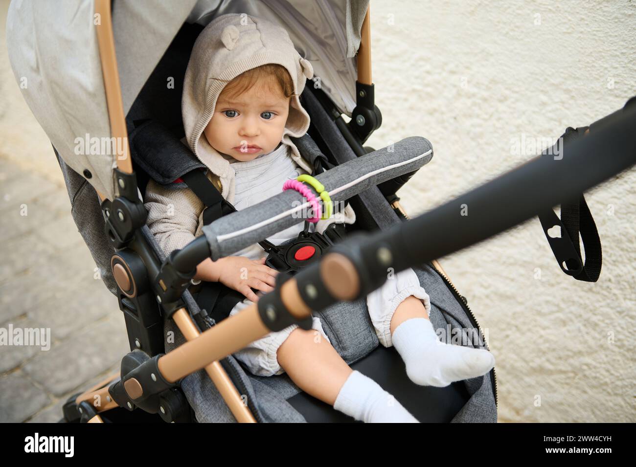 A cute baby boy in baby pram, stroller, pushchair during a family walk ...