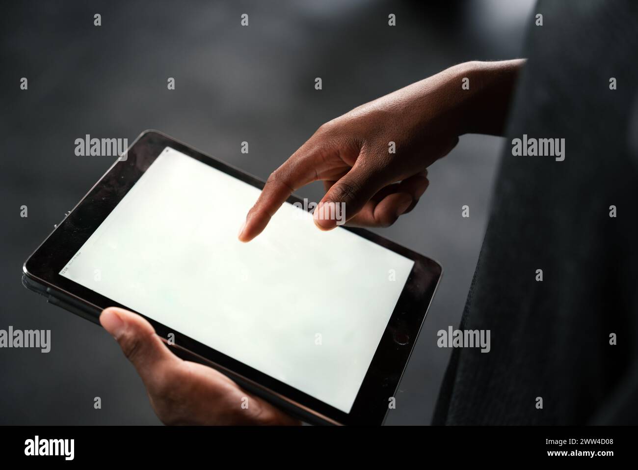 Hand holding tablet, pointing with finger at screen Stock Photo - Alamy