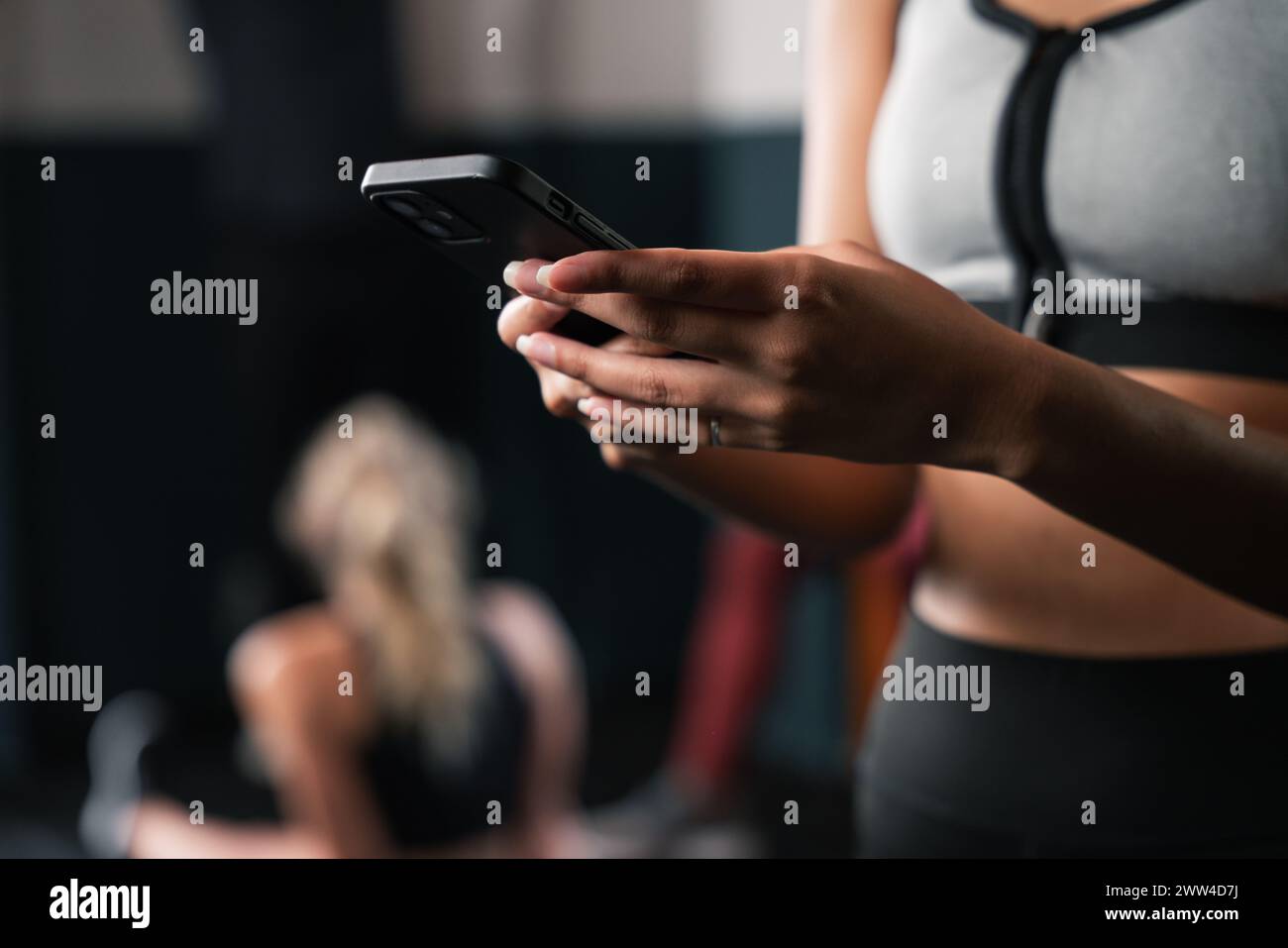 A woman gesturing with her hand using a communication device in the gym ...