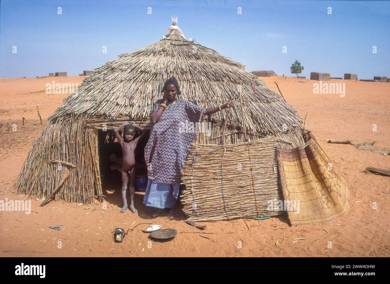 Niger, Tera province, mother and child in front of their thatched hut ...