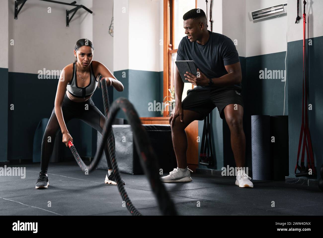 A man and a woman are building leg muscles with ropes in a gym Stock ...