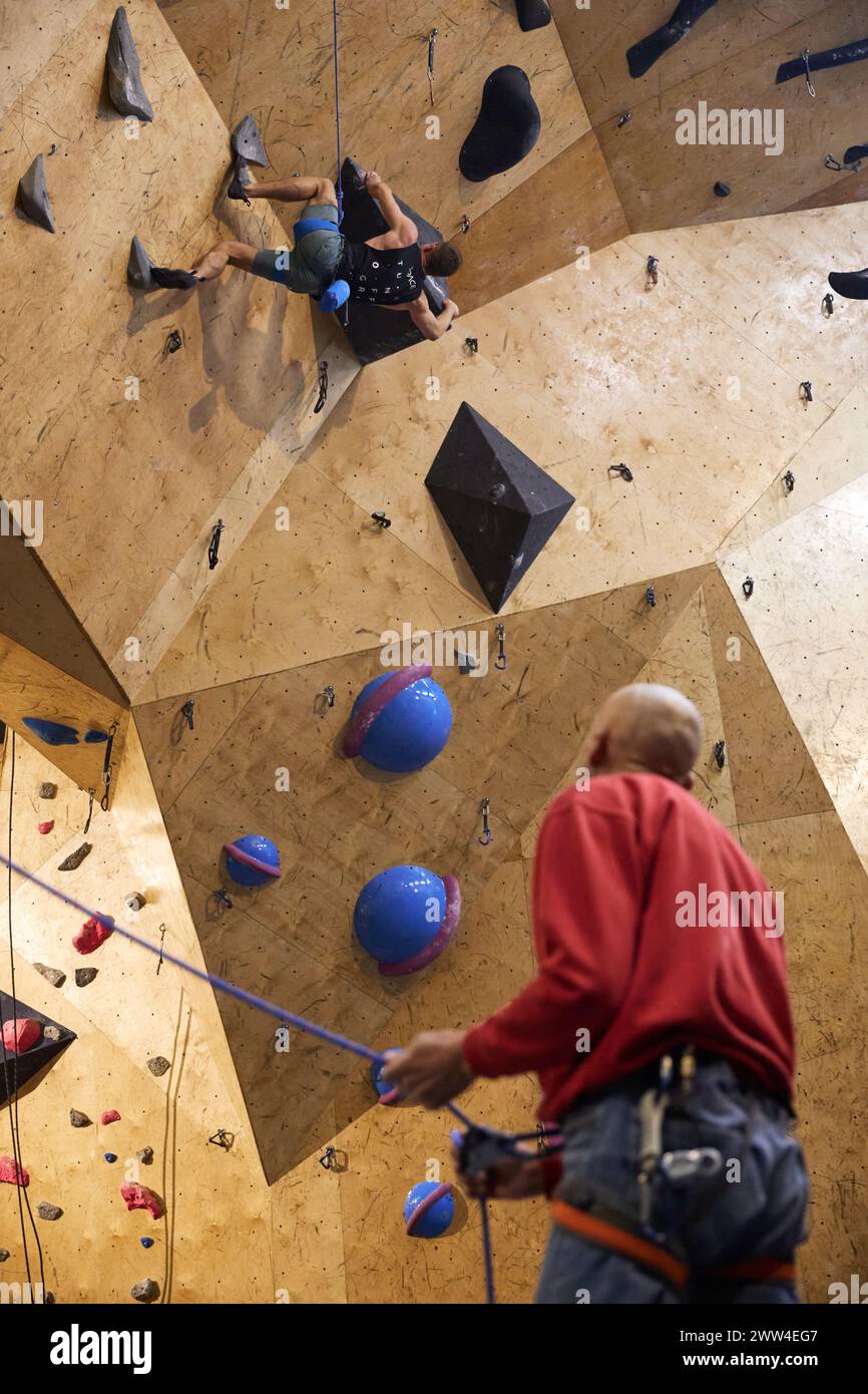 Professional climber hanging upside down on a high climbing wall while ...