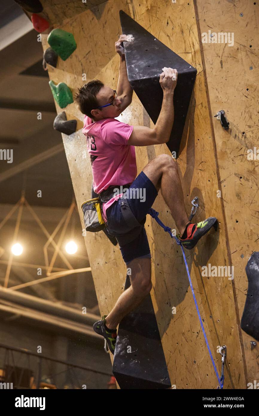 Professional climber climbing up the wall with grips at the competition ...