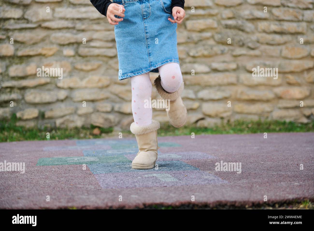 Details on the legs of an active little child girl playing hopscotch ...