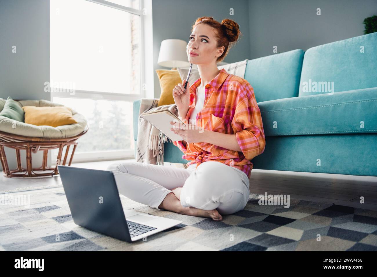 Full size photo of charming minded girl sit barefoot floor hold notepad pen use laptop bright ...