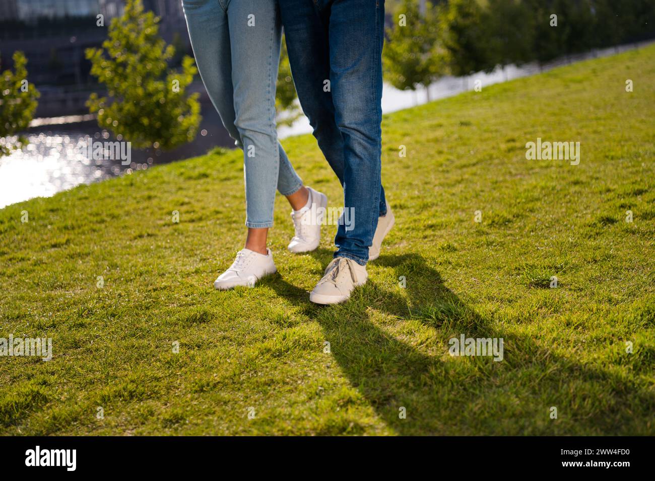 Cropped photo of two partners legs shadow footwear ad walking green ...