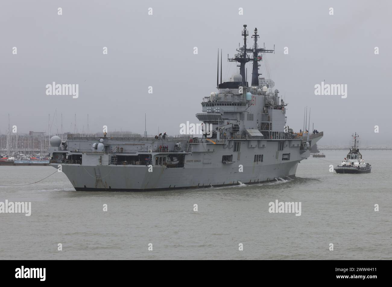 A tug guides the Italian Navy aircraft carrying cruiser ITS GIUSEPPE ...