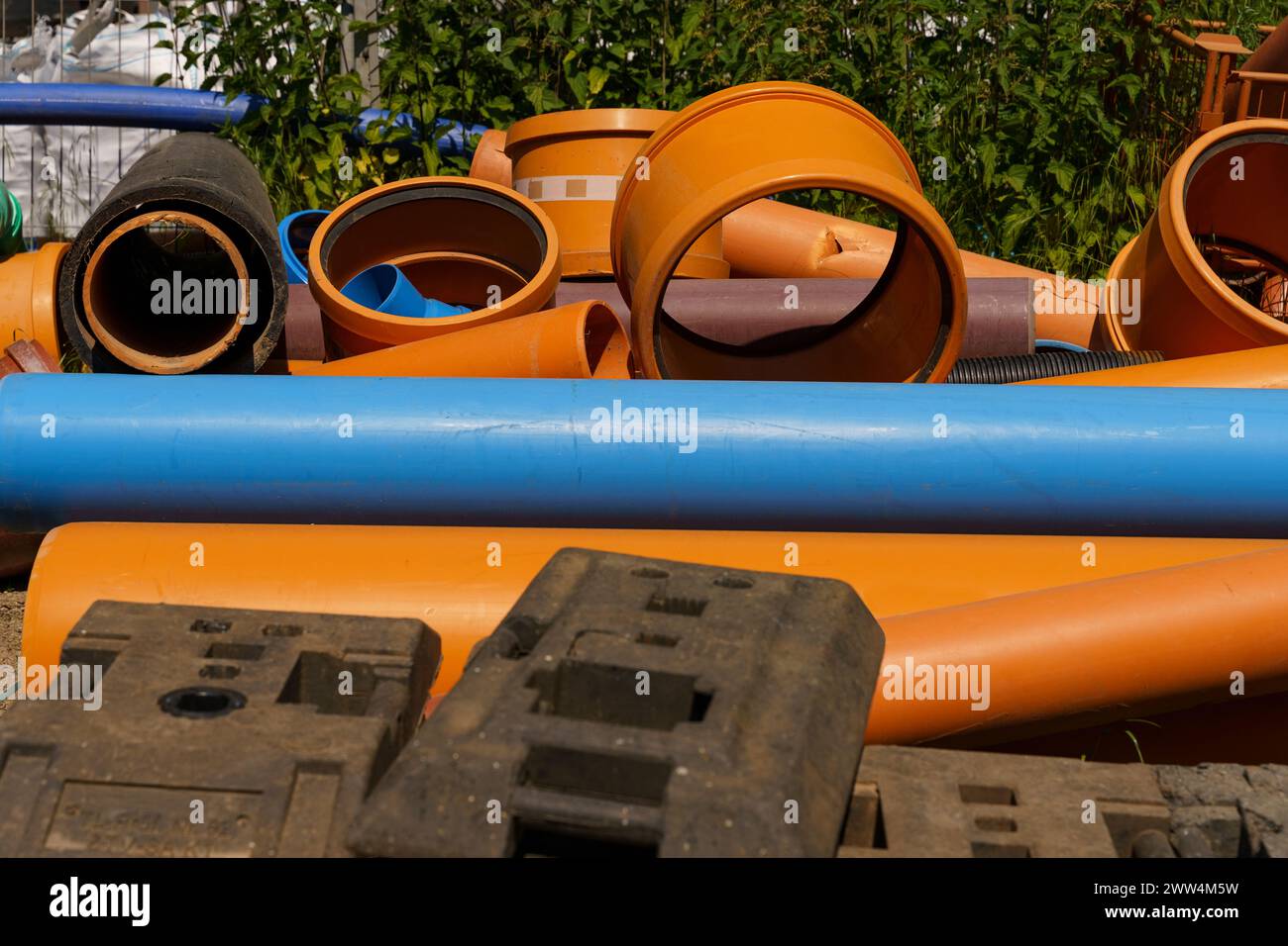 A collection of orange and blue pipes stacked next to each other in an ...
