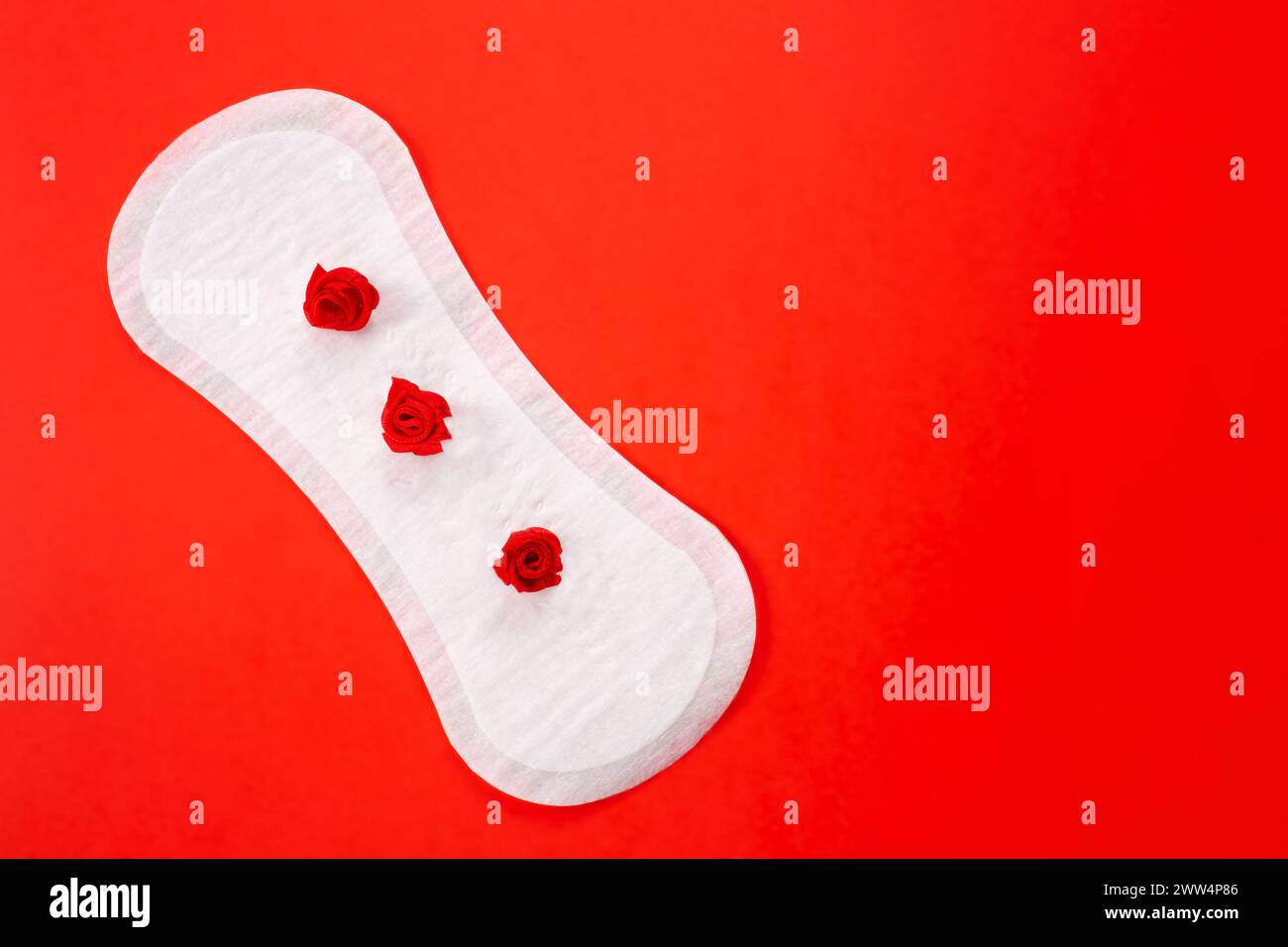 Feminine hygiene pad with red flowers on pink background. First ...