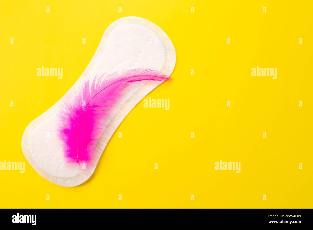 Blood and feminine hygiene pad with feather on yellow background. First ...