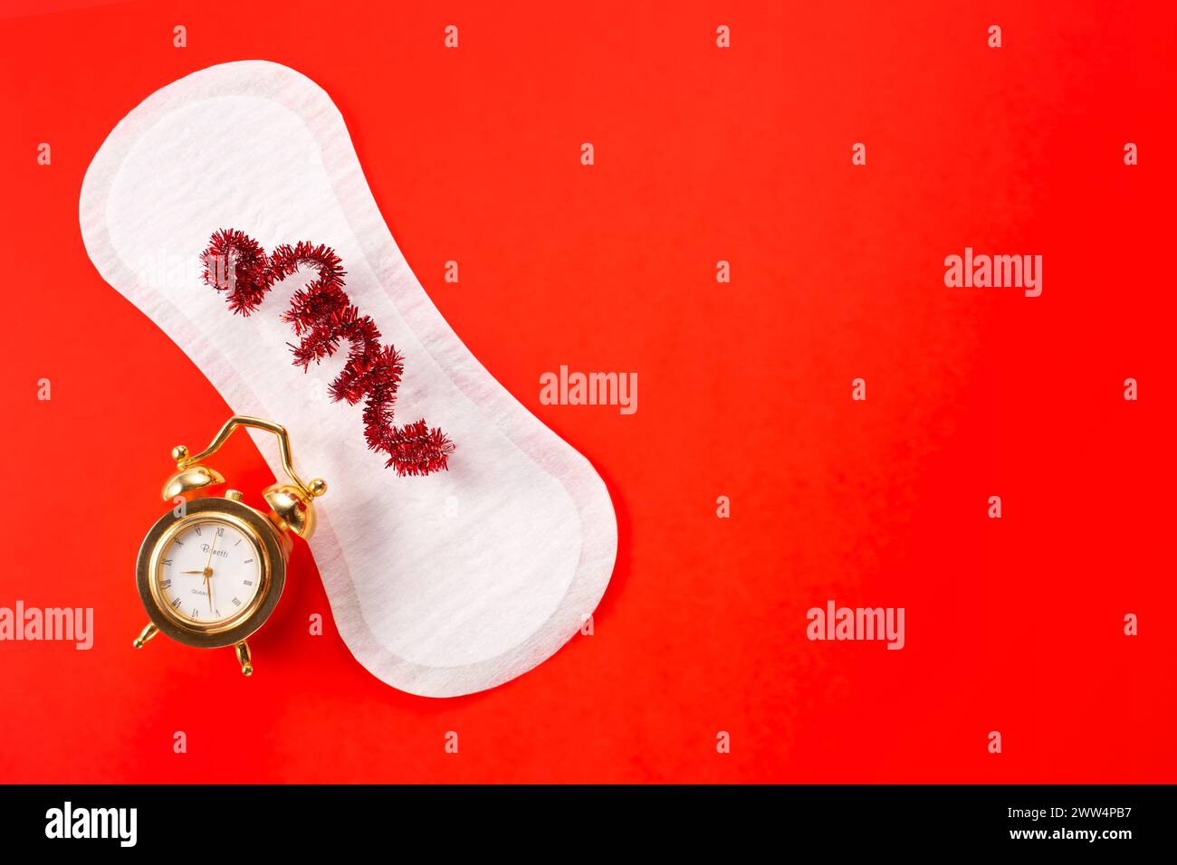 Alarm clock and feminine hygiene pad on red background. First menstrual ...