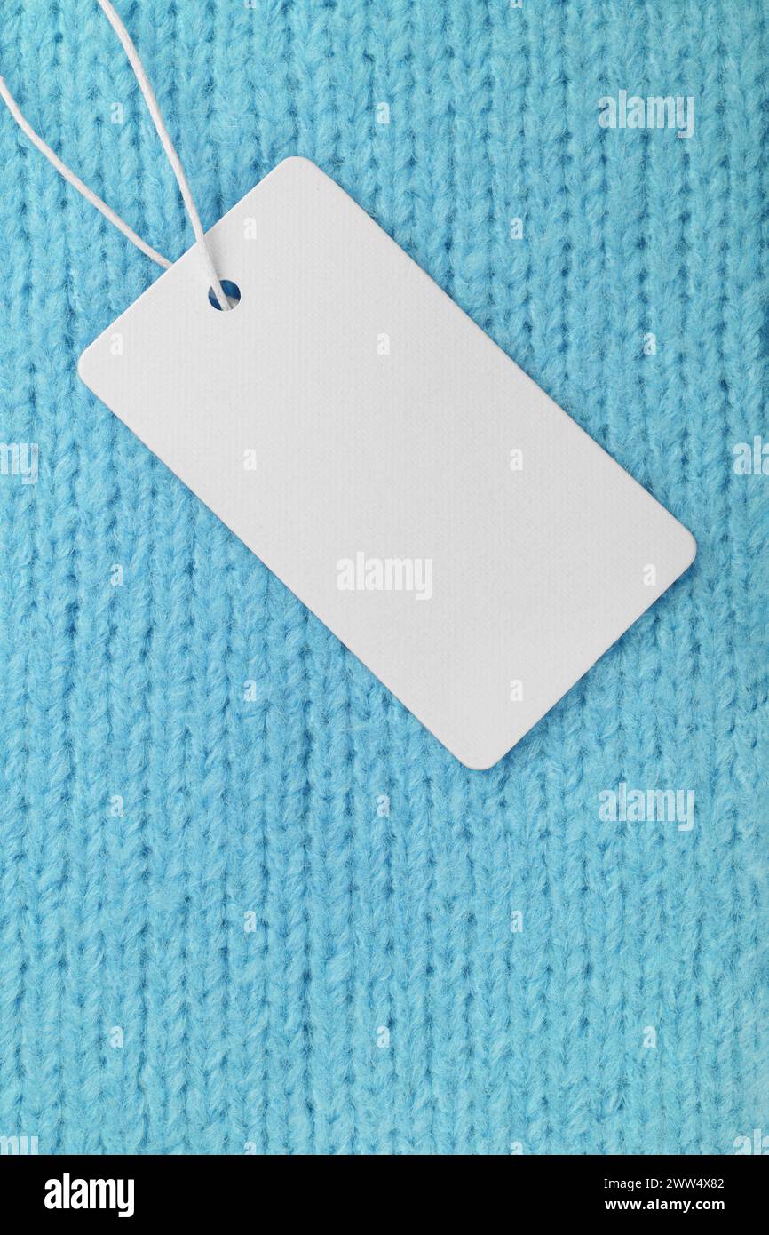 Blank clothing label on turquoise knitted sweater background. Mockup ...