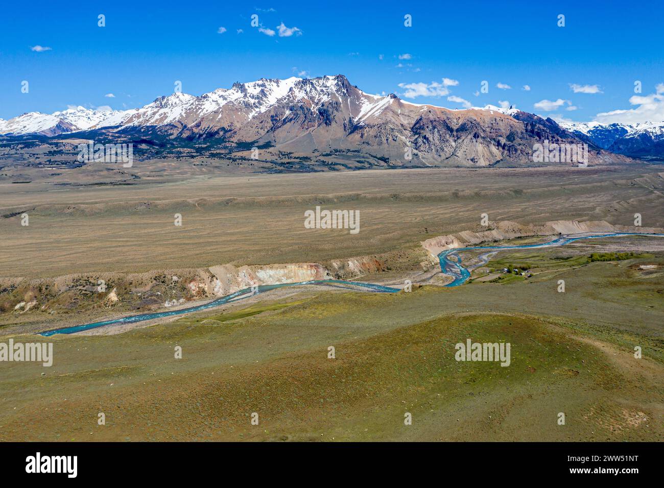 River flows in a canyon in front of snow-capped volcanic mountains ...