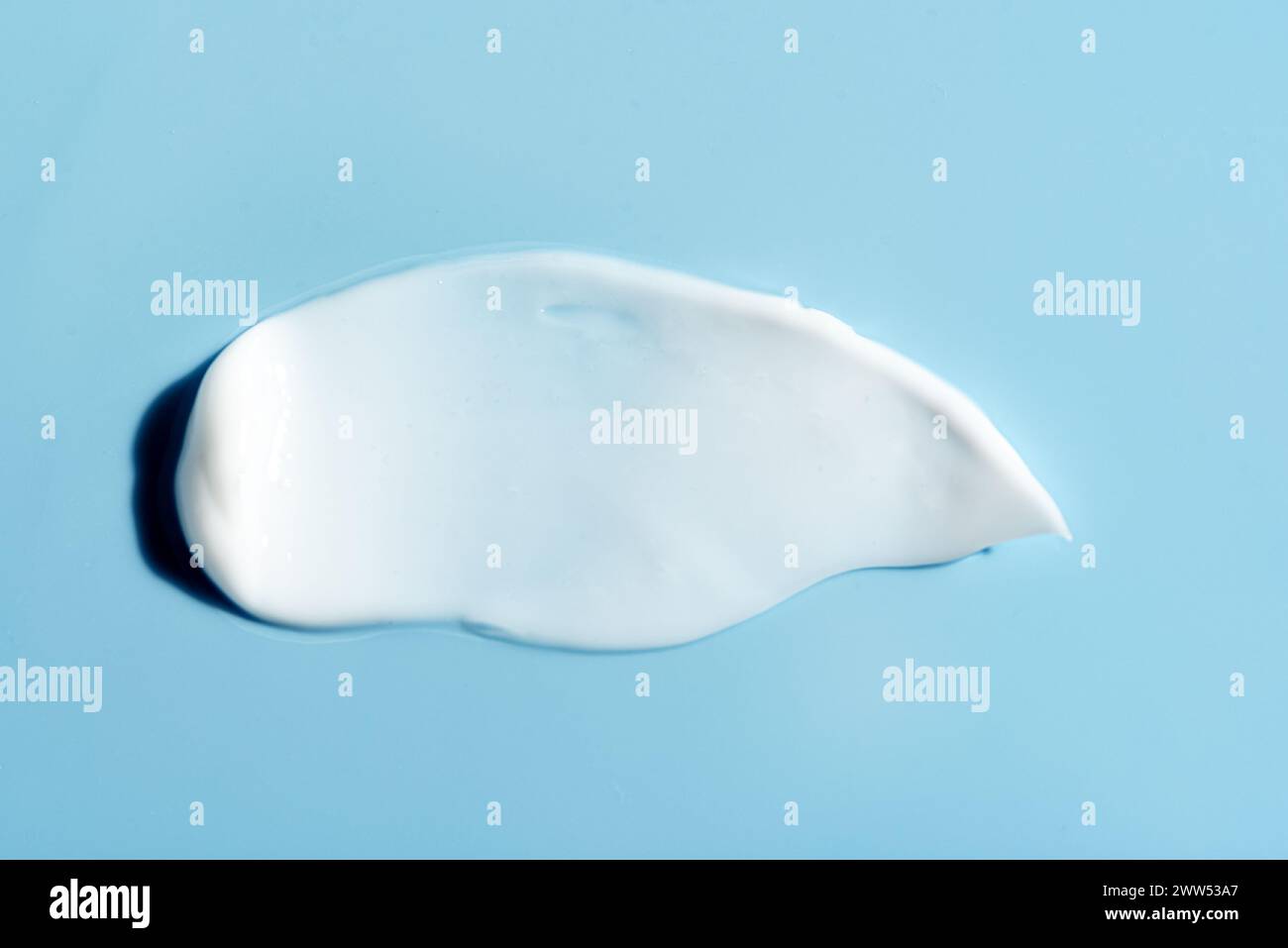 Texture of white cream on blue background. Smear swatch of moisturizer ...