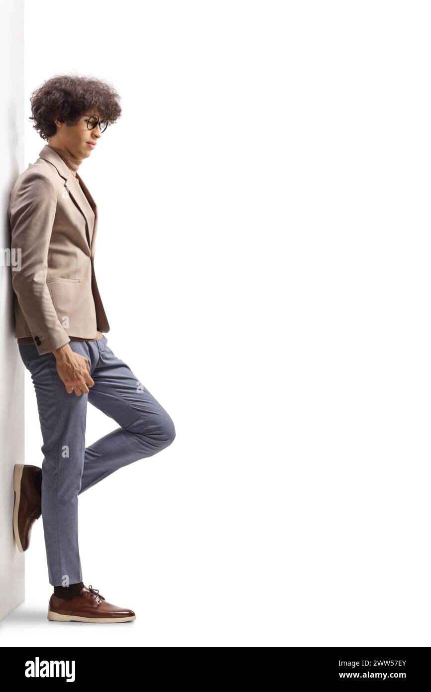 Young clever man leaning on a wall and thinking isolated on white ...