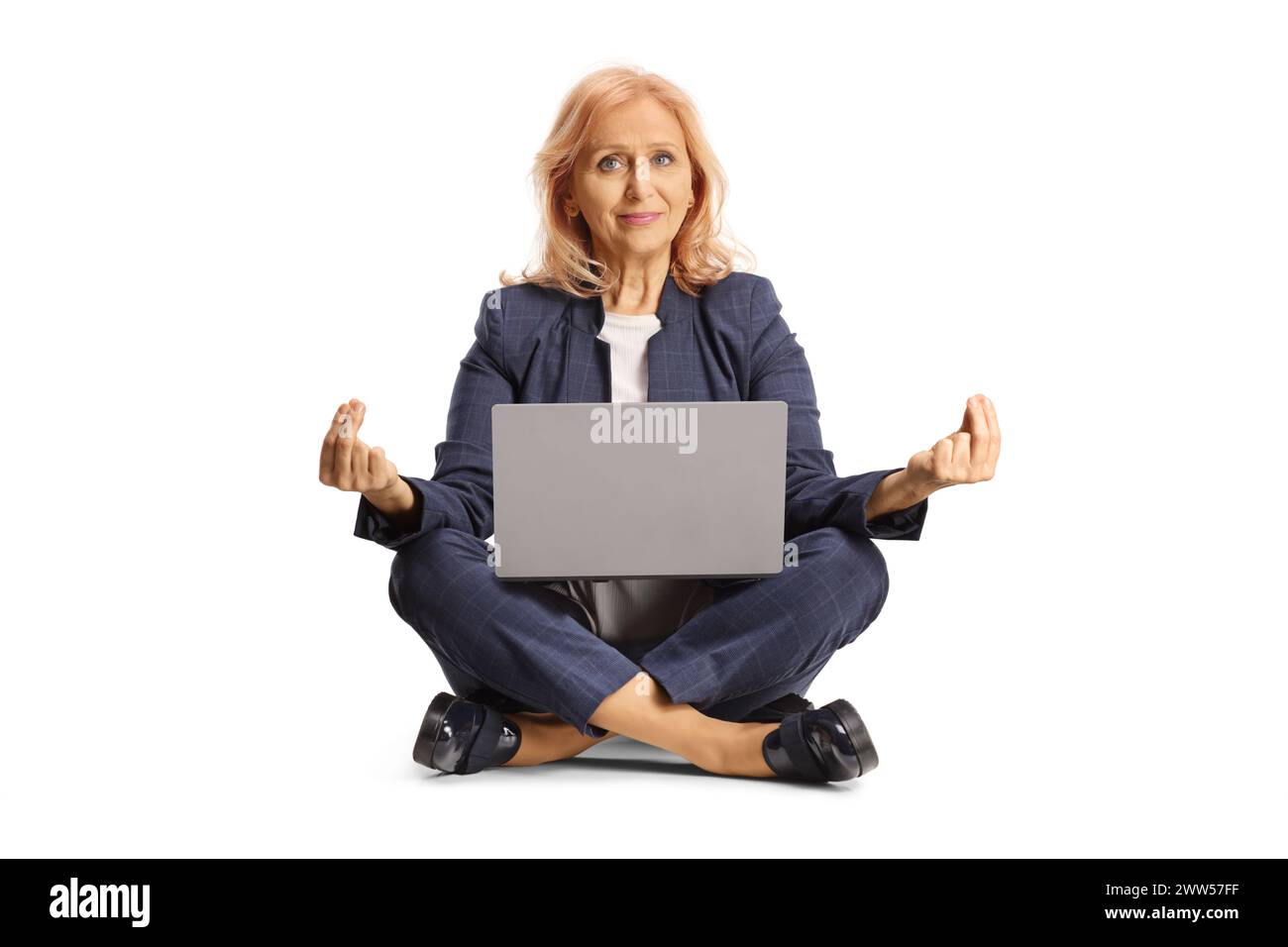 Businesswoman with a laptop computer sitting in a meditation pose ...